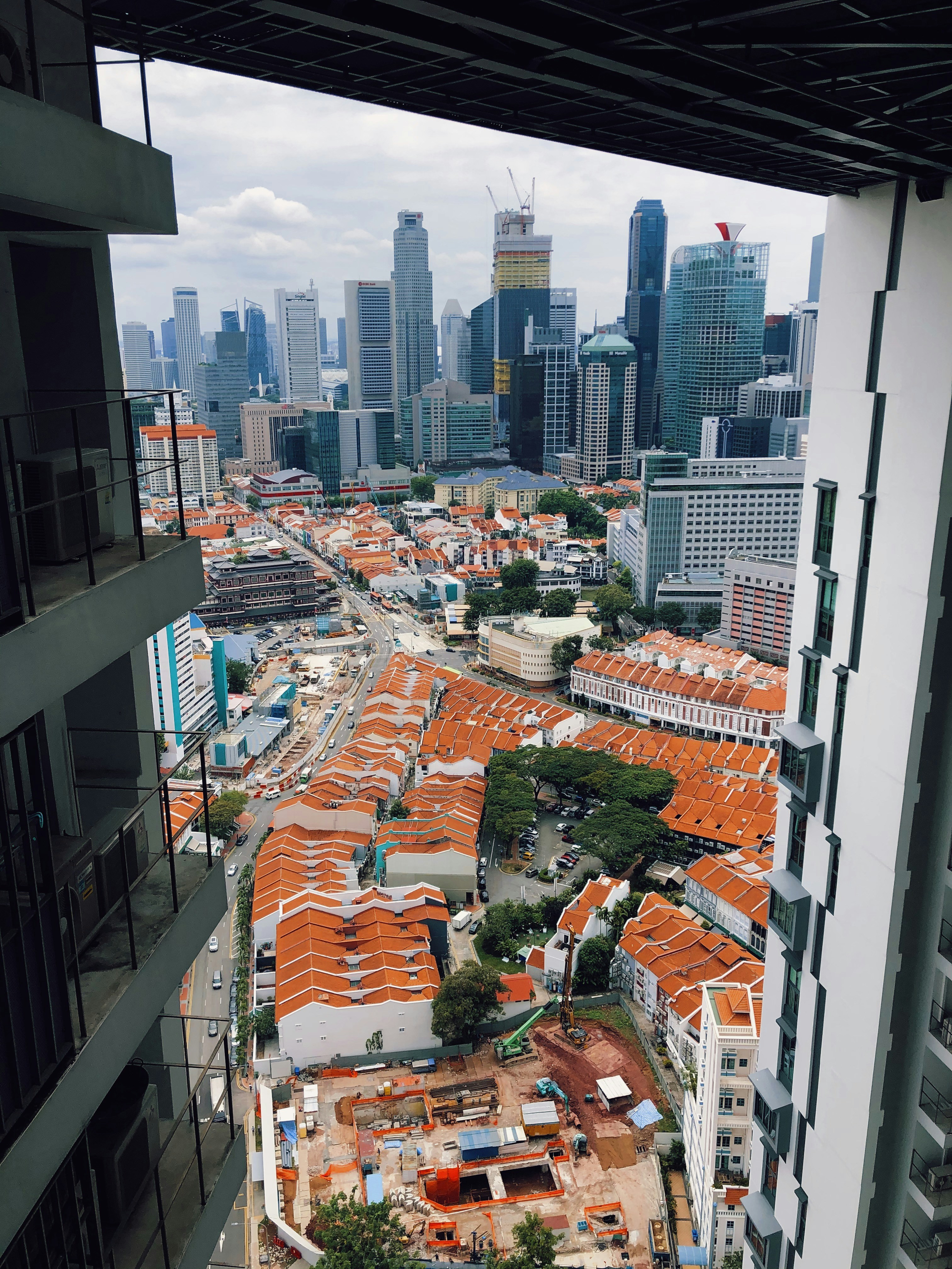 View from a high-rise showcasing a blend of modern skyscrapers and traditional shophouses in Singapore, with construction activity visible below.