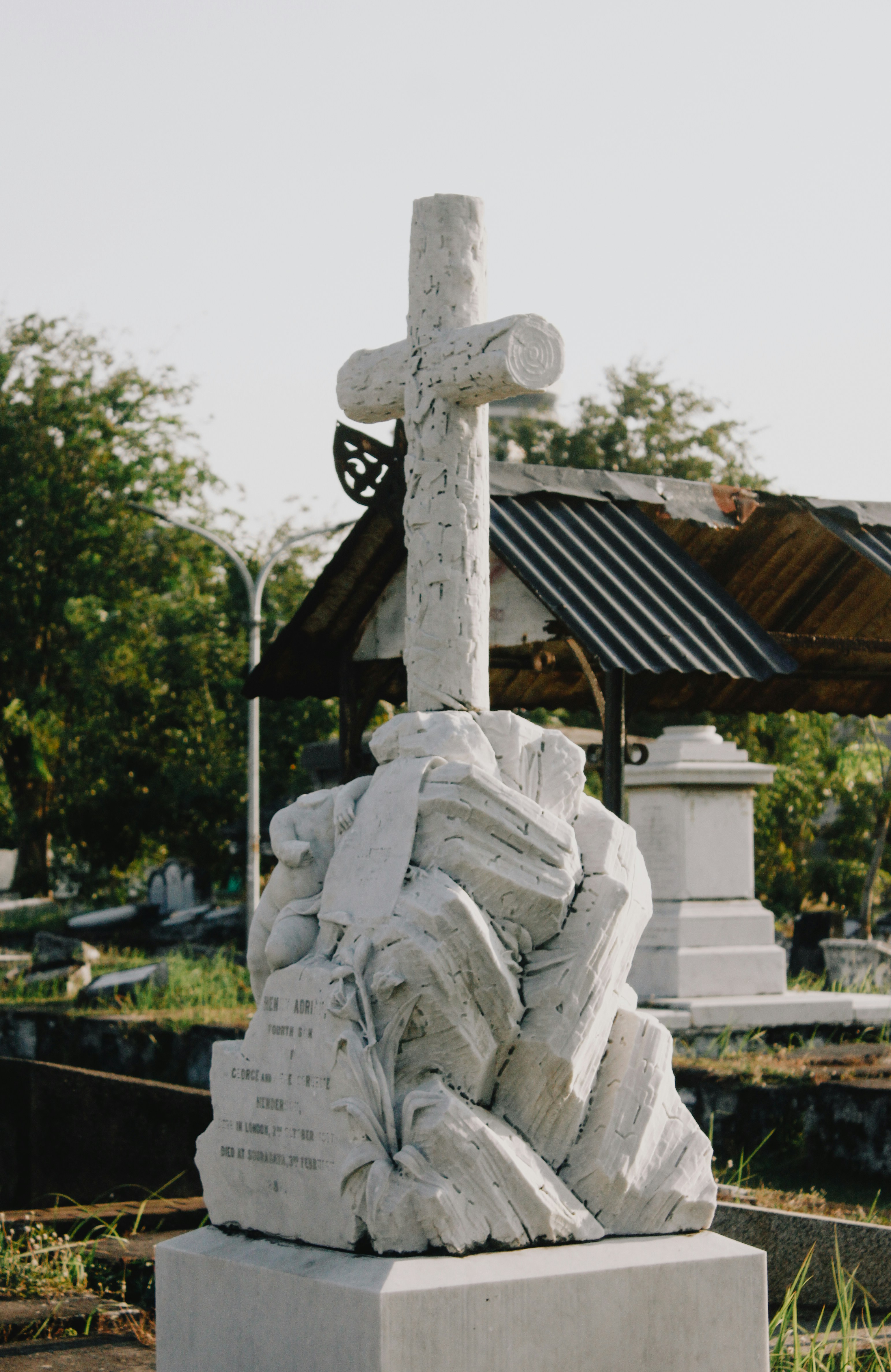 Cross of Stone: A Weathered Monument Beneath a Corrugated Shelter