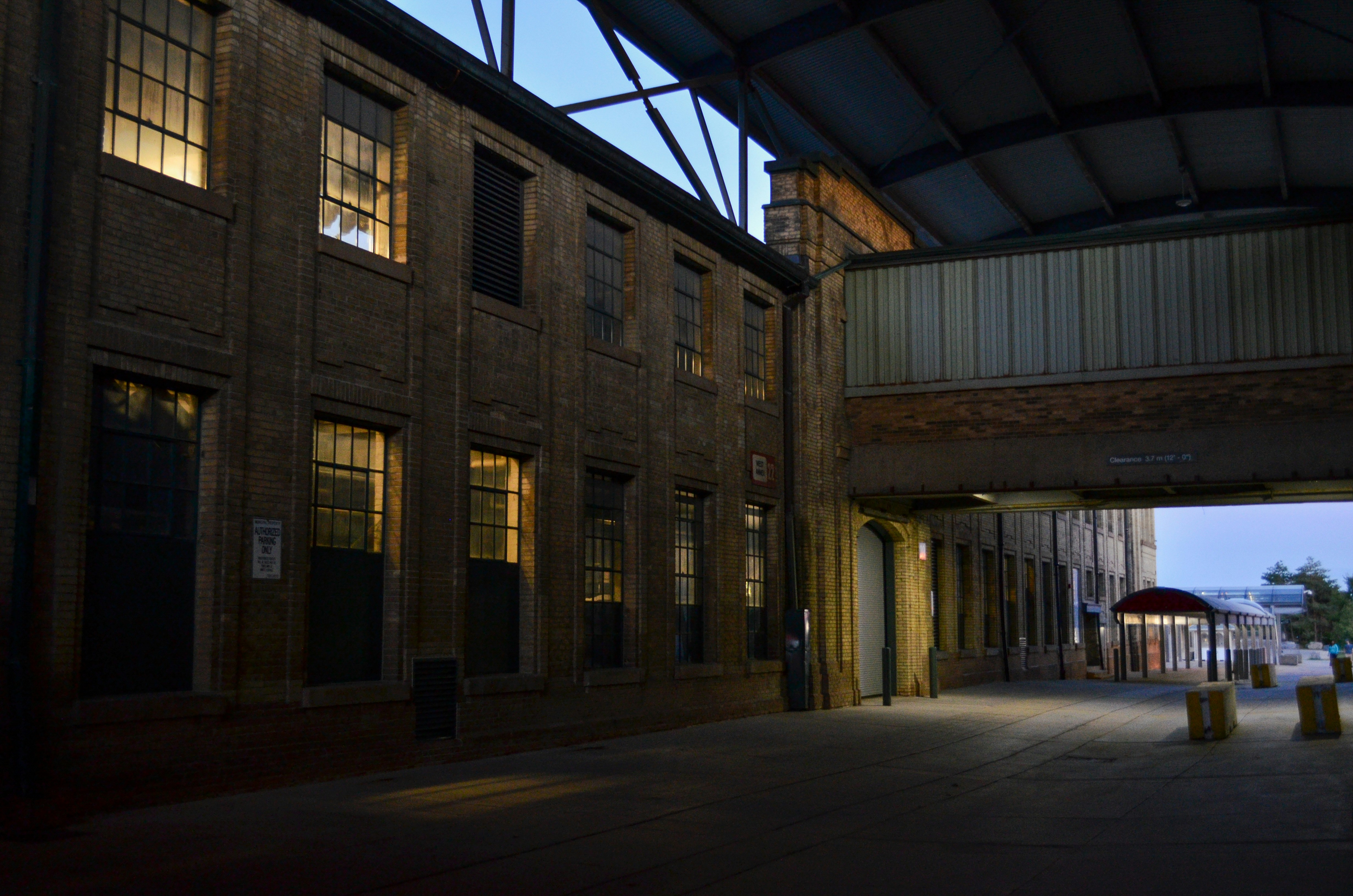 Dusk Beneath the Canopy: Warm Window Light on an Old Brick Factory Courtyard