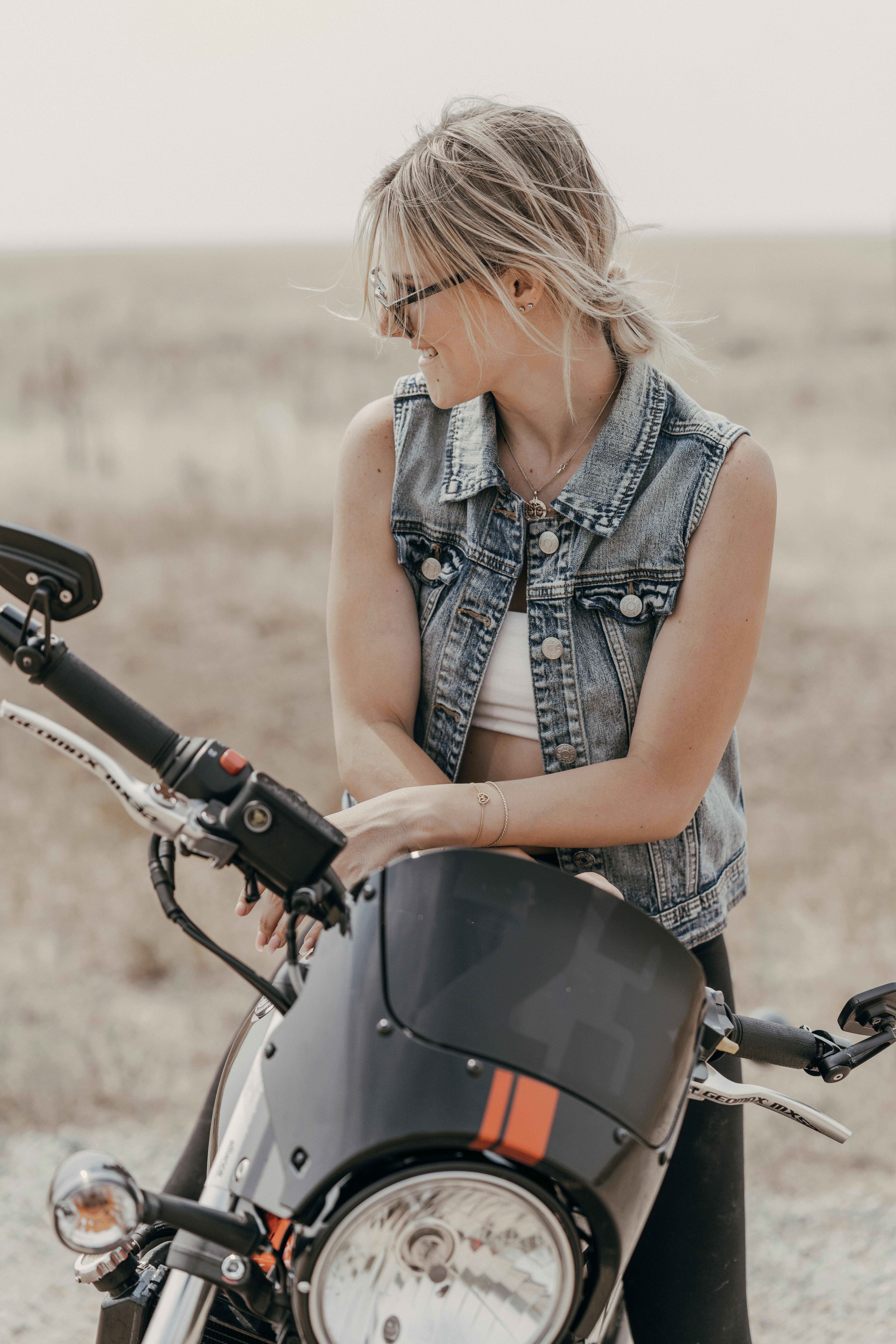 Sunlit Moment: Woman in Denim Vest with Moto at the Edge of the Field