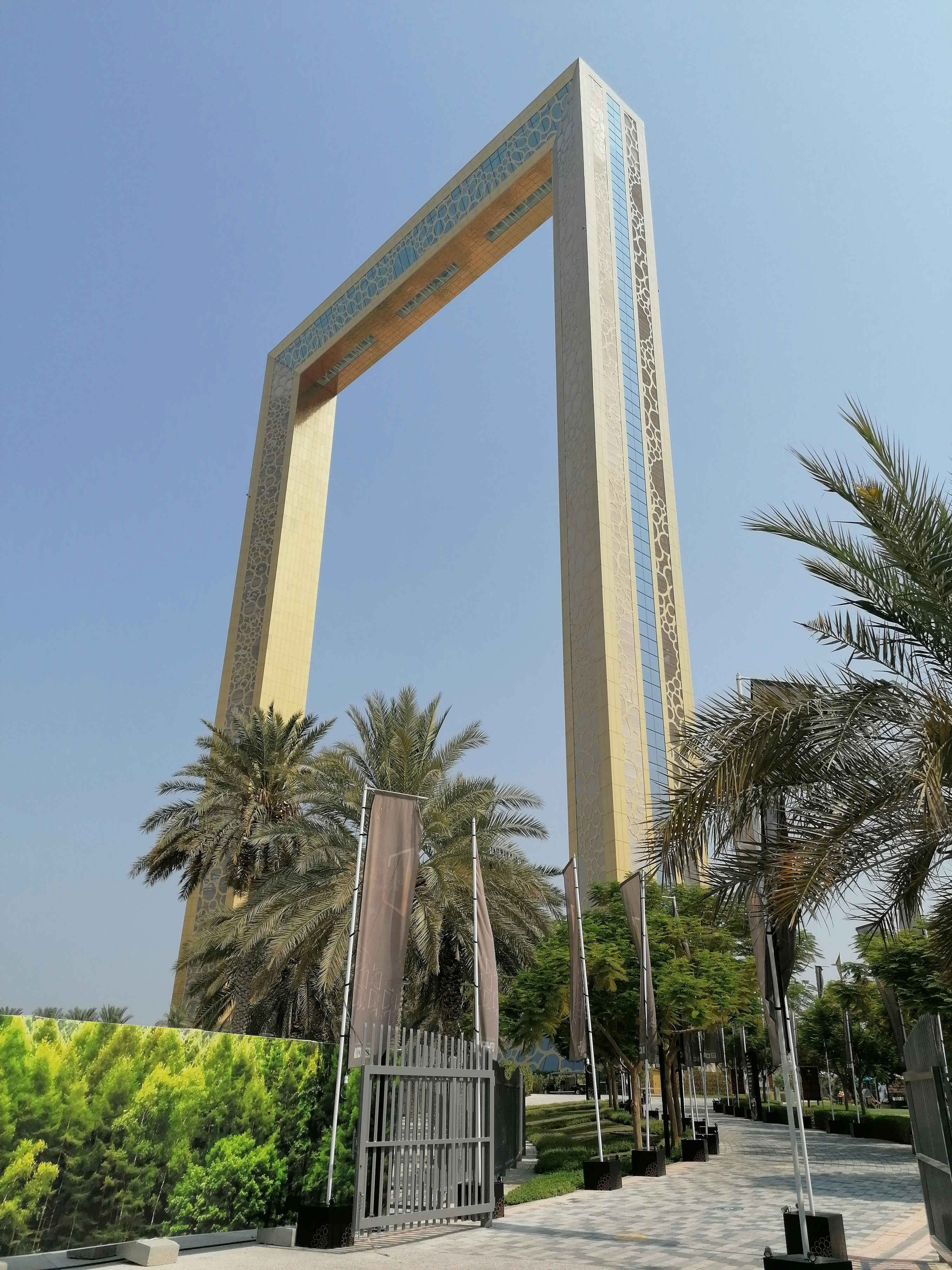 Architectural structure framed by palm trees, showcasing a contemporary design against a clear blue sky.