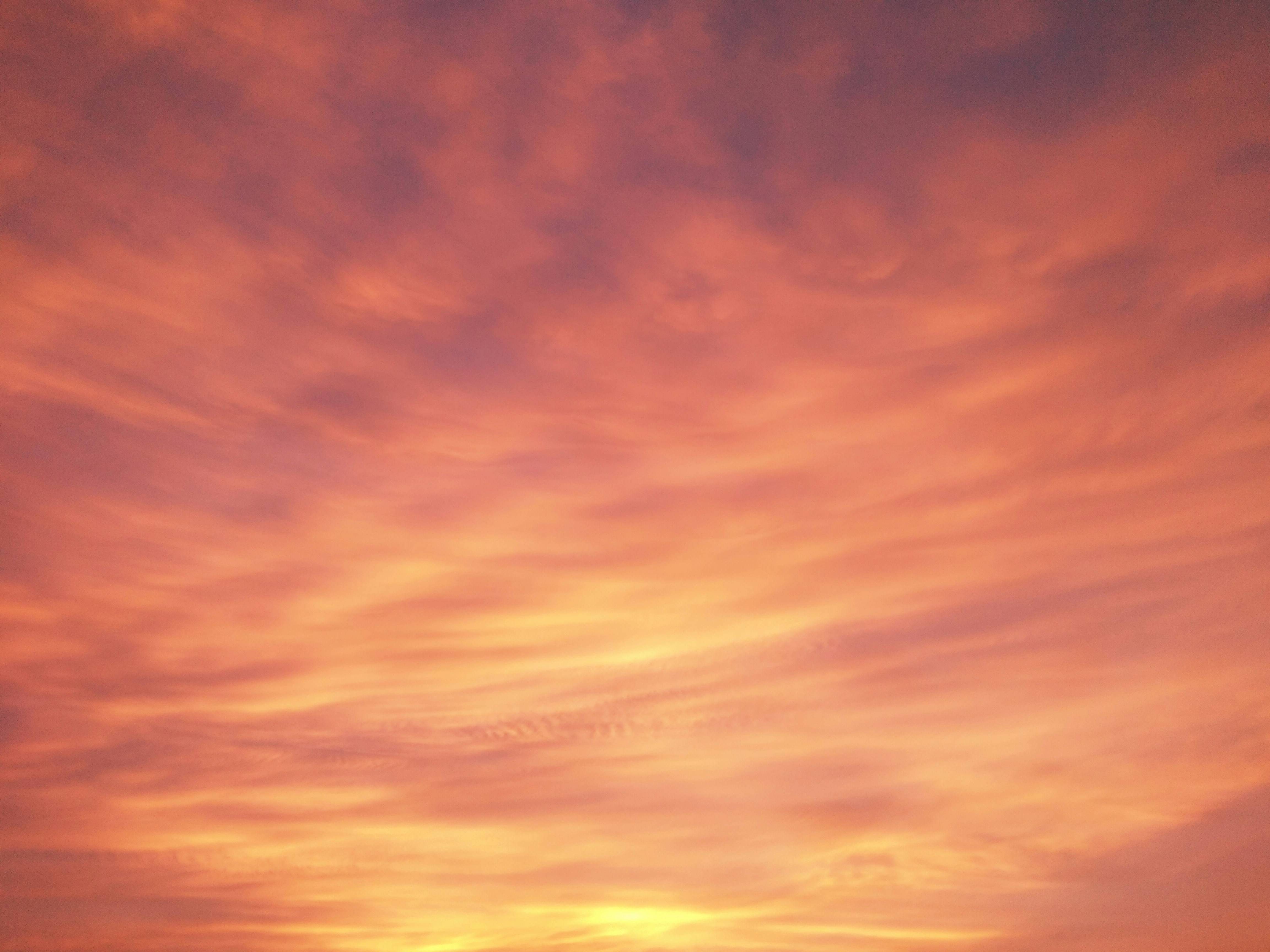 A vibrant display of clouds painted in hues of orange and pink during sunset, creating a serene atmosphere.