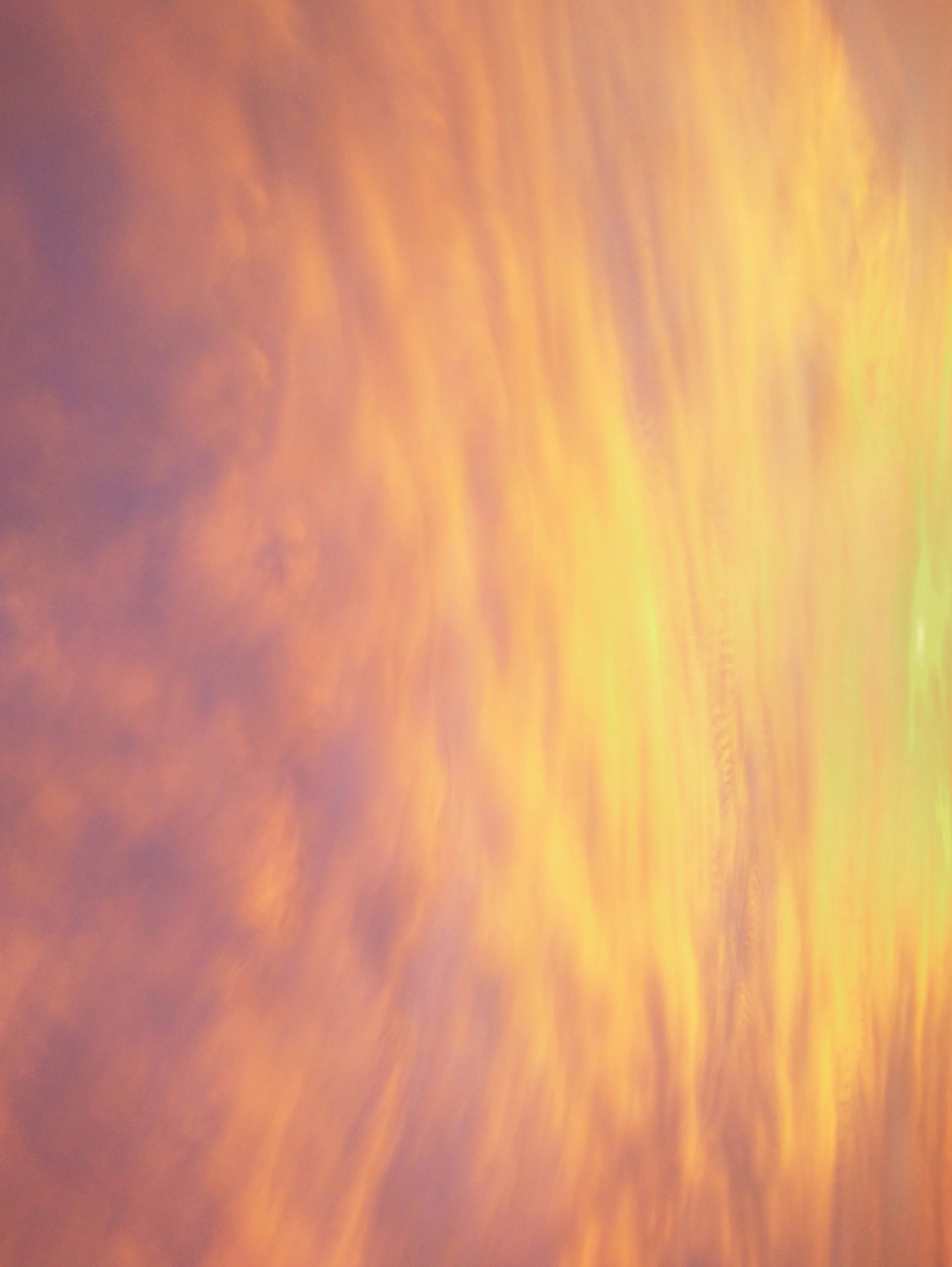 Vibrant clouds painted in hues of orange and purple during sunset, creating a serene sky. The interplay of light and color evokes a sense of tranquility.