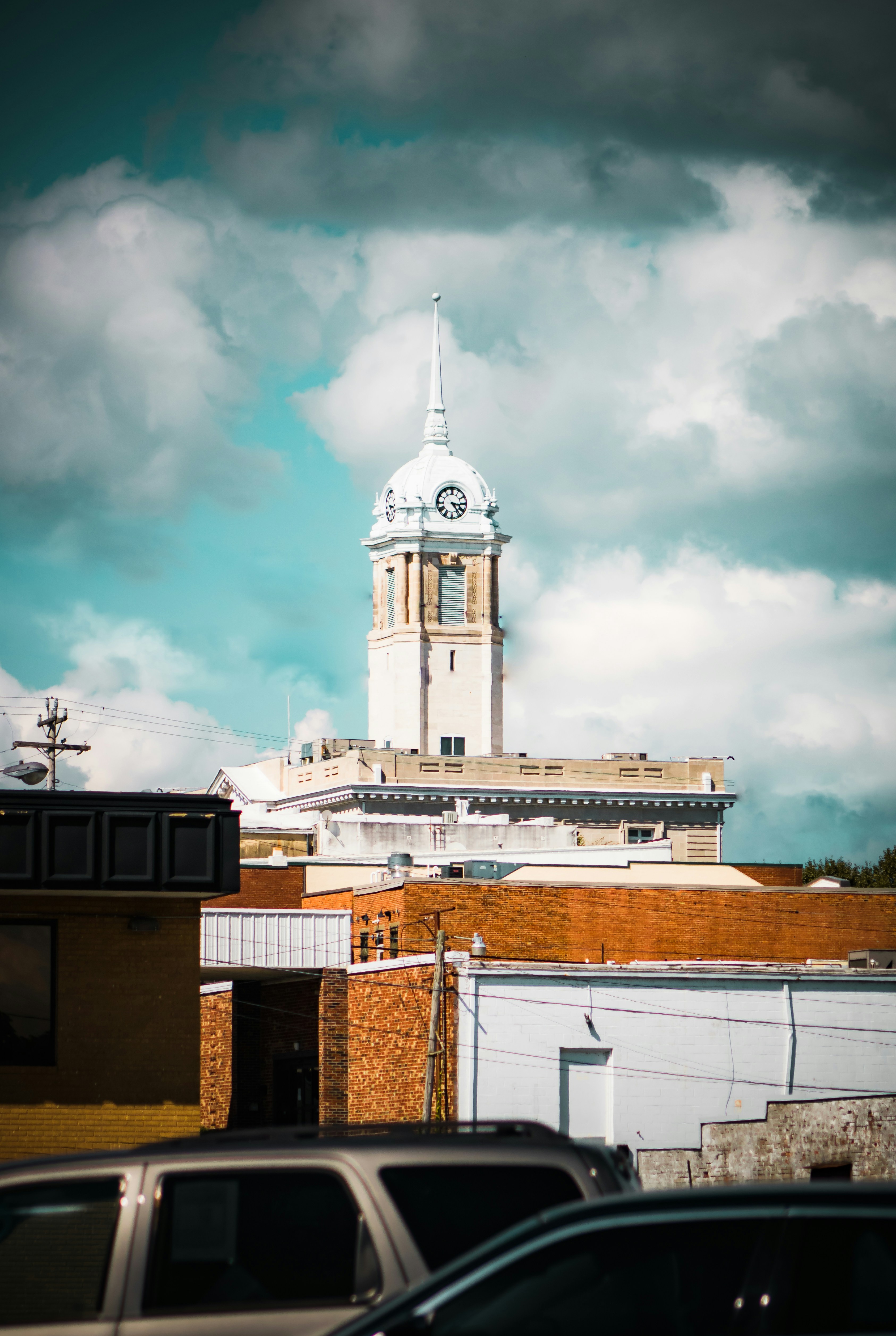 Historic clocktower rising above urban rooftops under a vibrant sky.