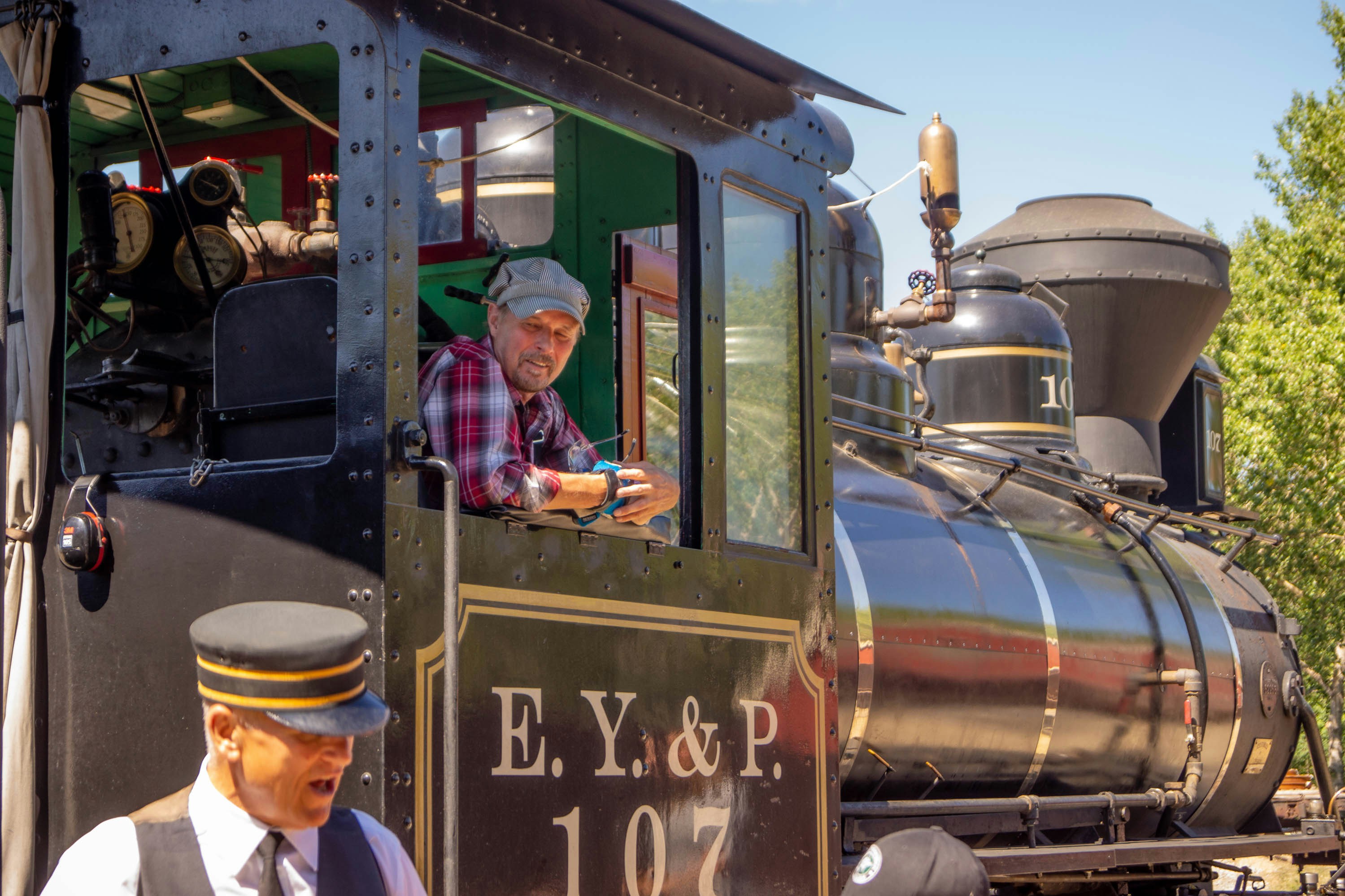 Engineer operating a vintage steam locomotive, showcasing the intricate details of the train's cabin and machinery. The scene reflects a moment of historical significance.