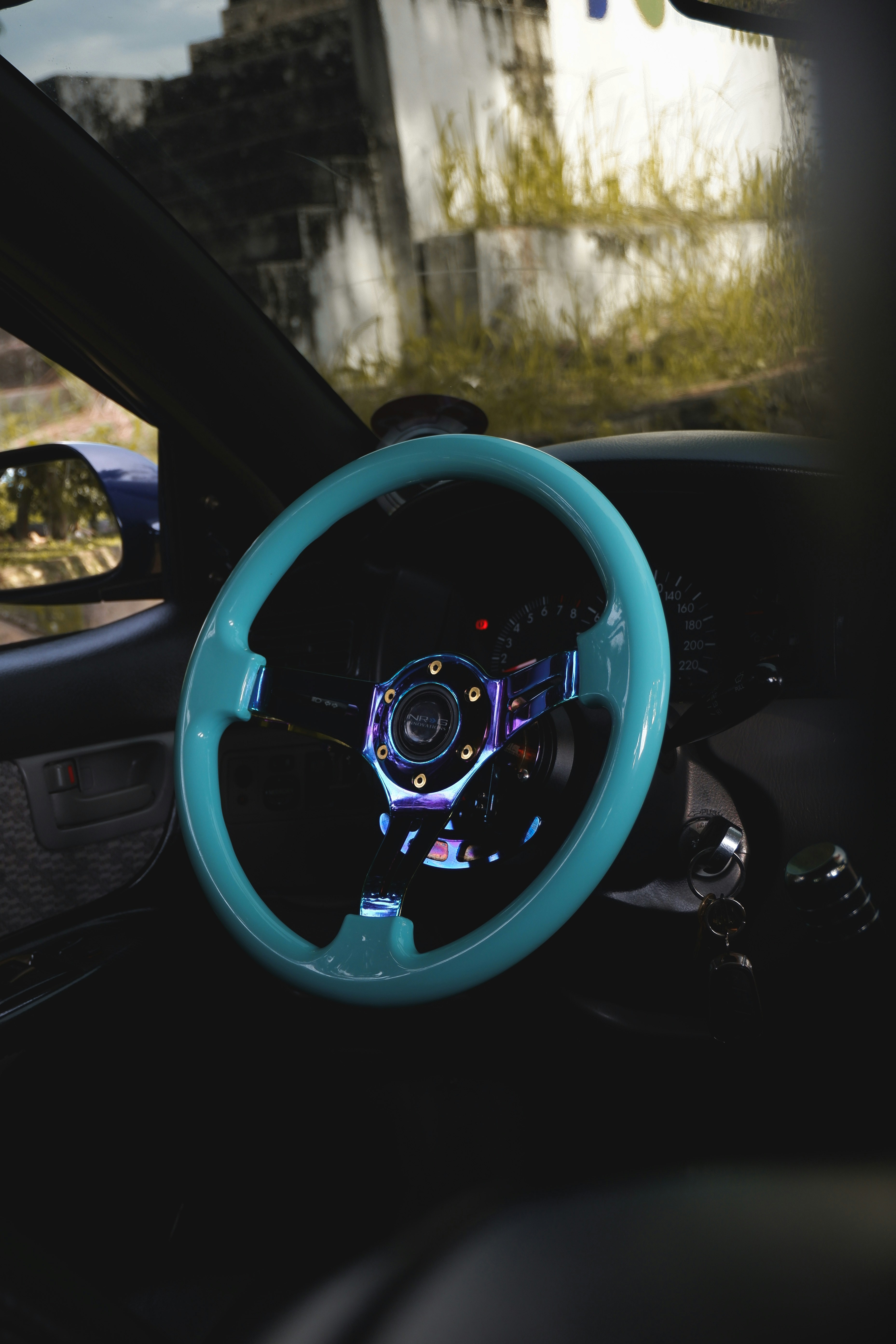 Teal Steering Wheel in a Shadowed Car Cabin: A Study in Craft and Contrast