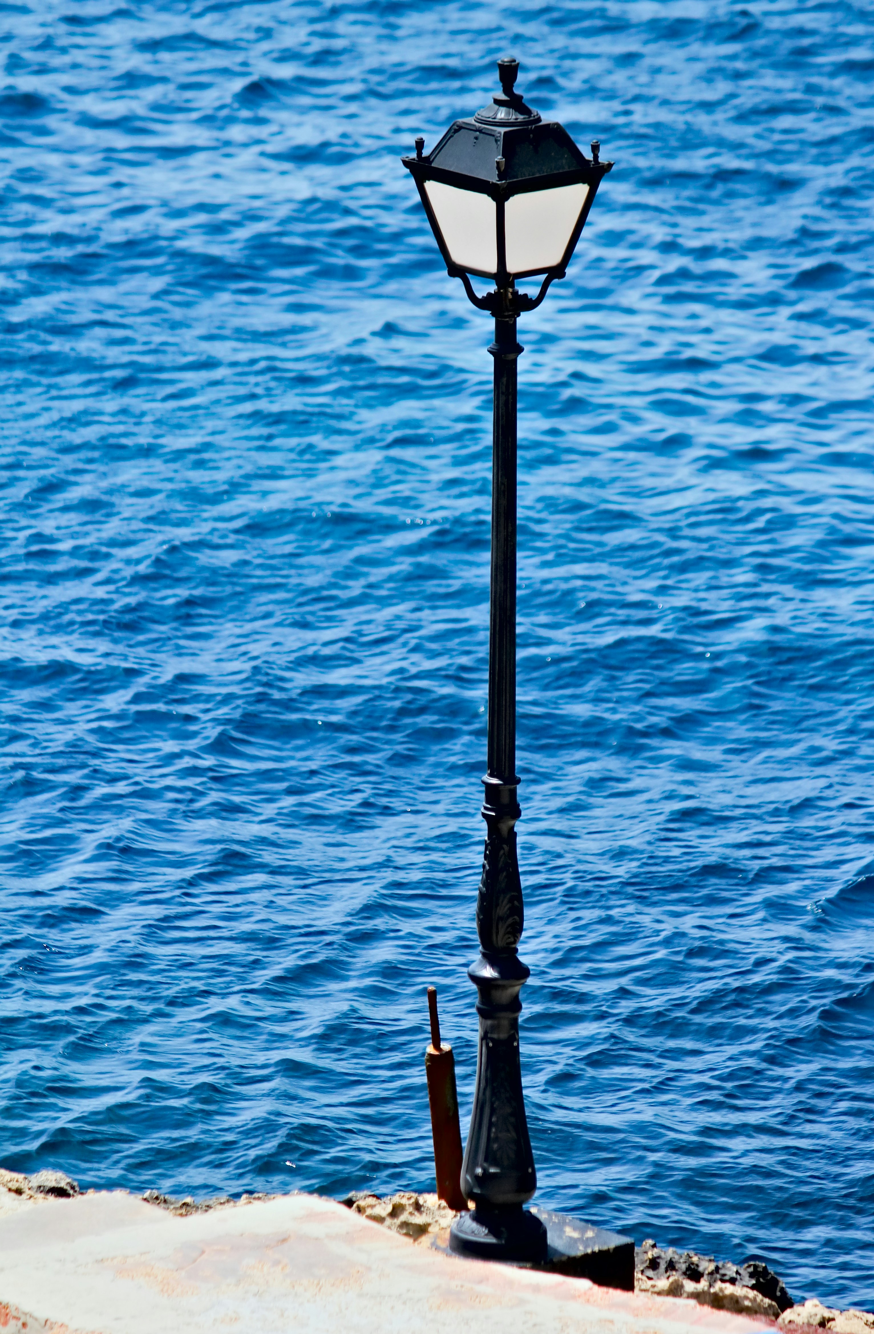 black and white street light near blue body of water during daytime