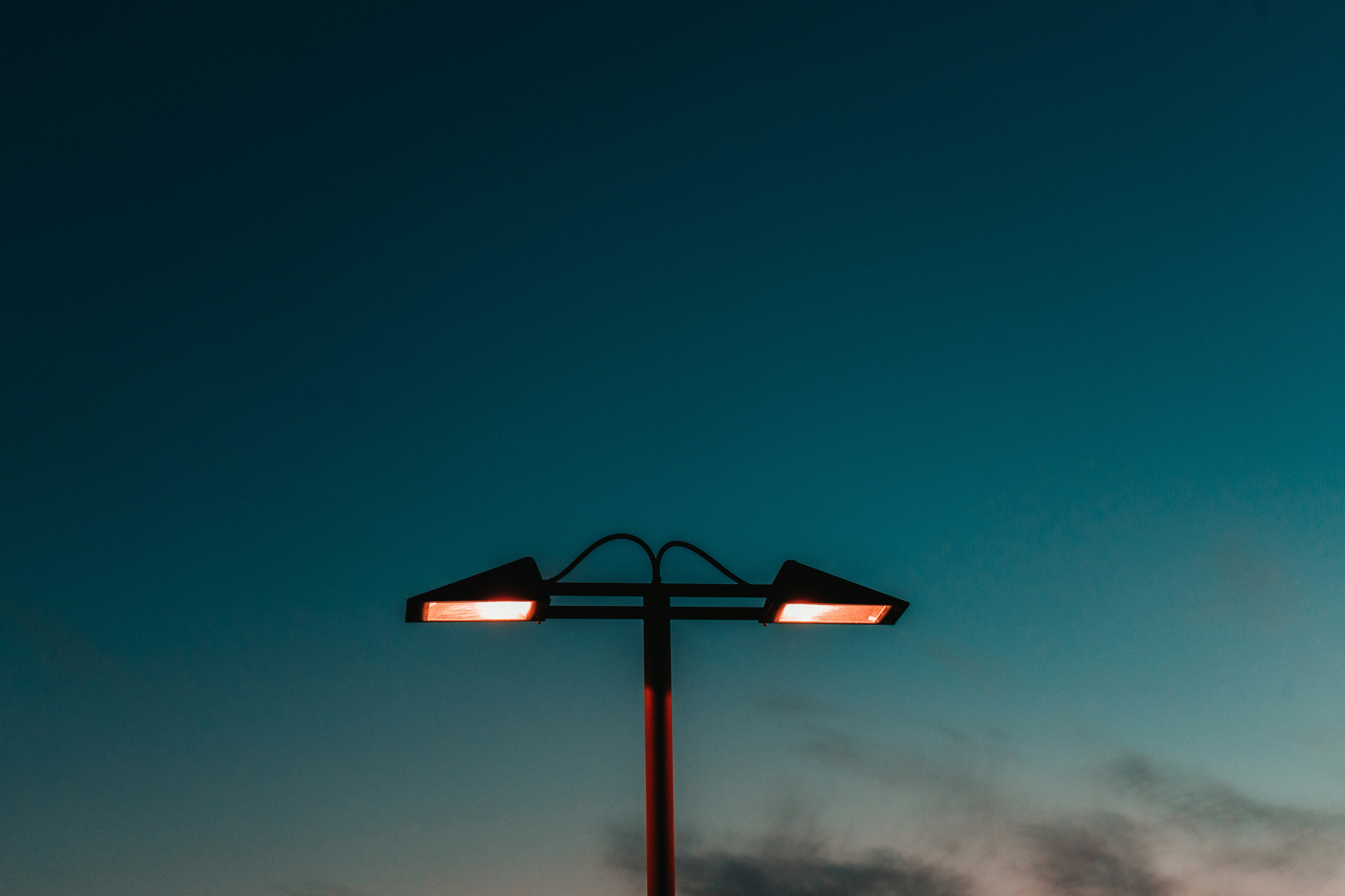A solitary streetlight casts a warm glow against a twilight sky, highlighting the contrast between artificial light and natural dusk.