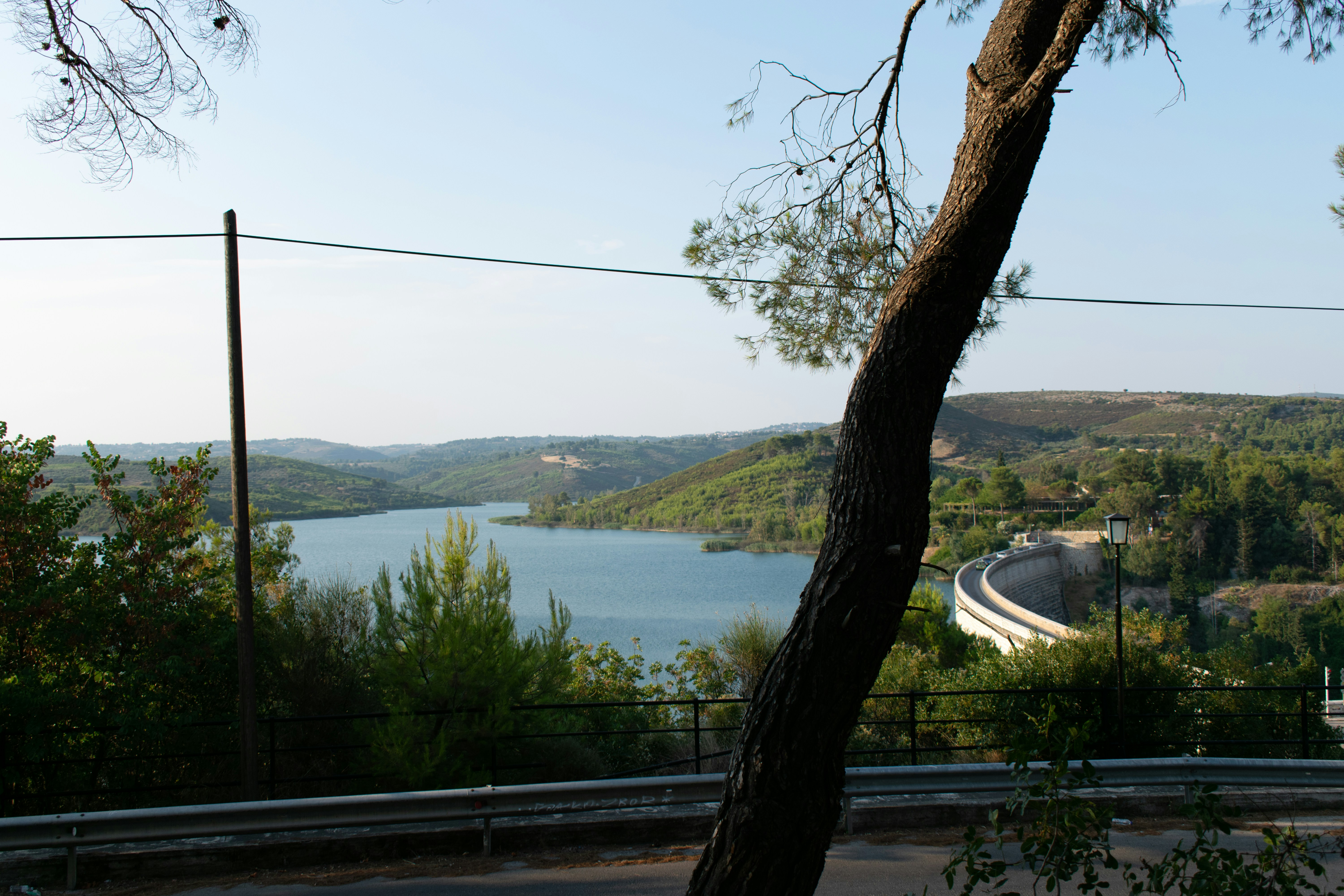 A tranquil view of a winding river surrounded by lush hills and trees, showcasing the harmony of nature and human engineering.