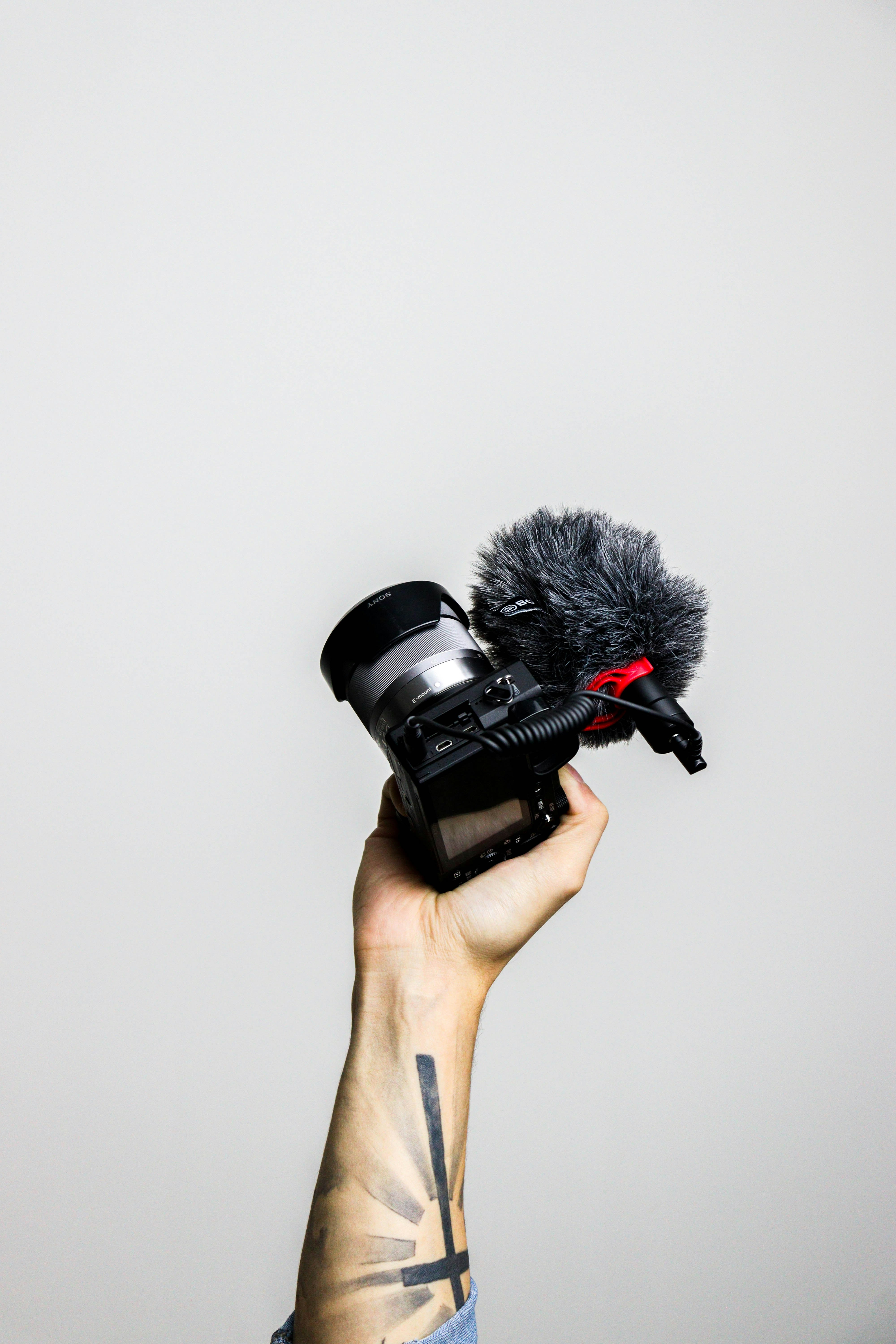 In the Hand: A compact camera rig with a furry microphone against a pale studio backdrop