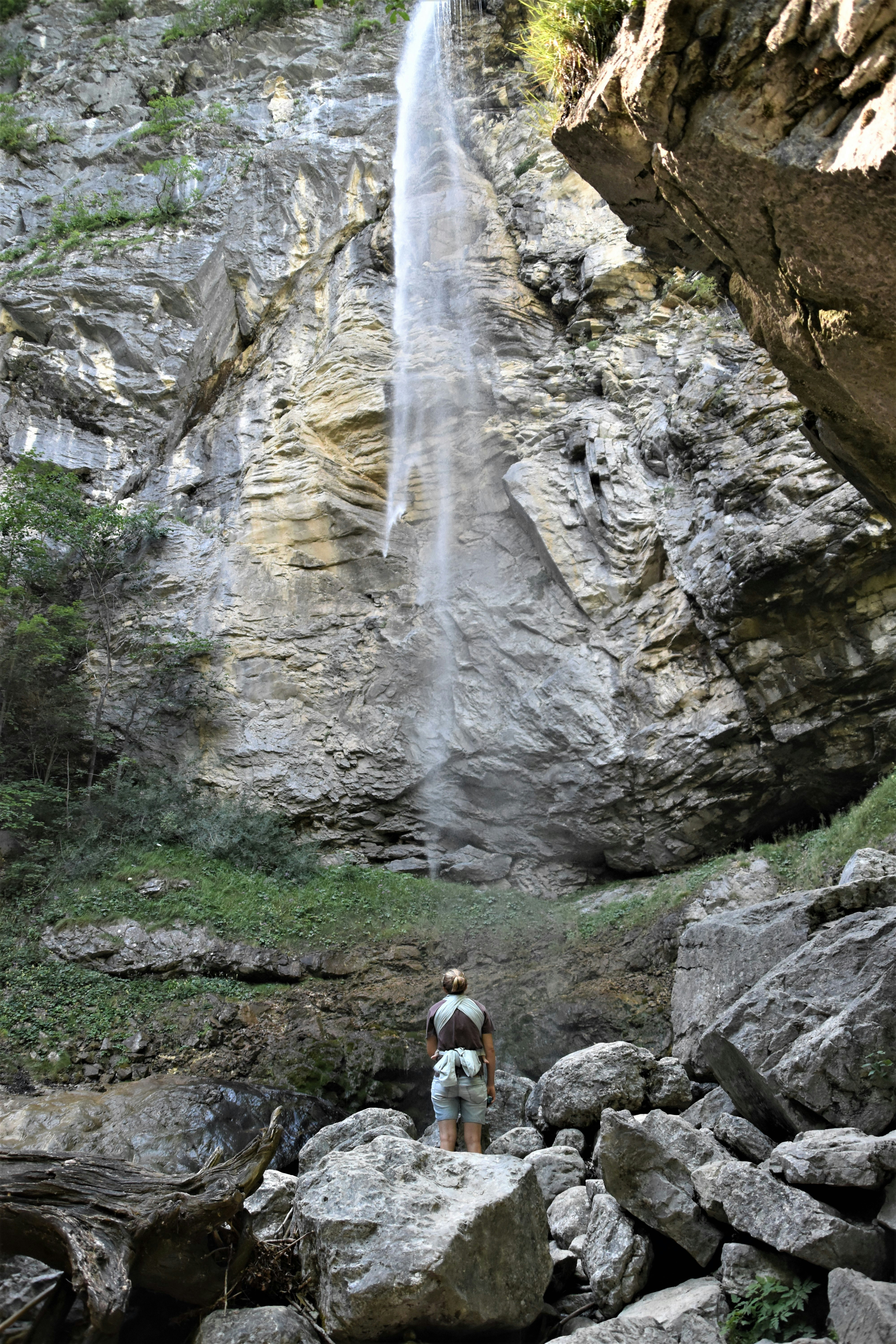 A mother with her baby breathes the waterfall drops and pure air of nature
