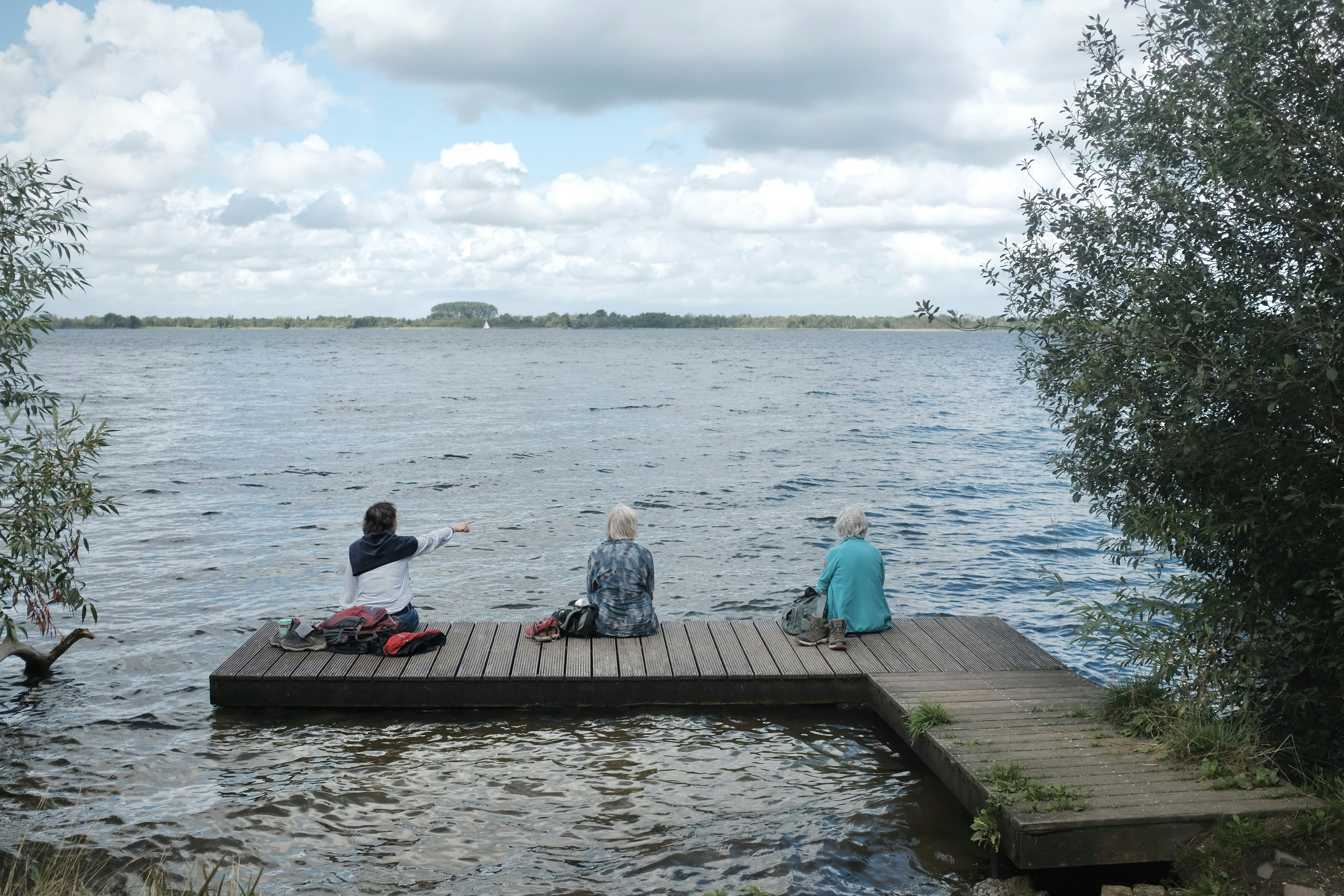 3 elderly people enjoying the view over the lake while keeping their social distance perfect.