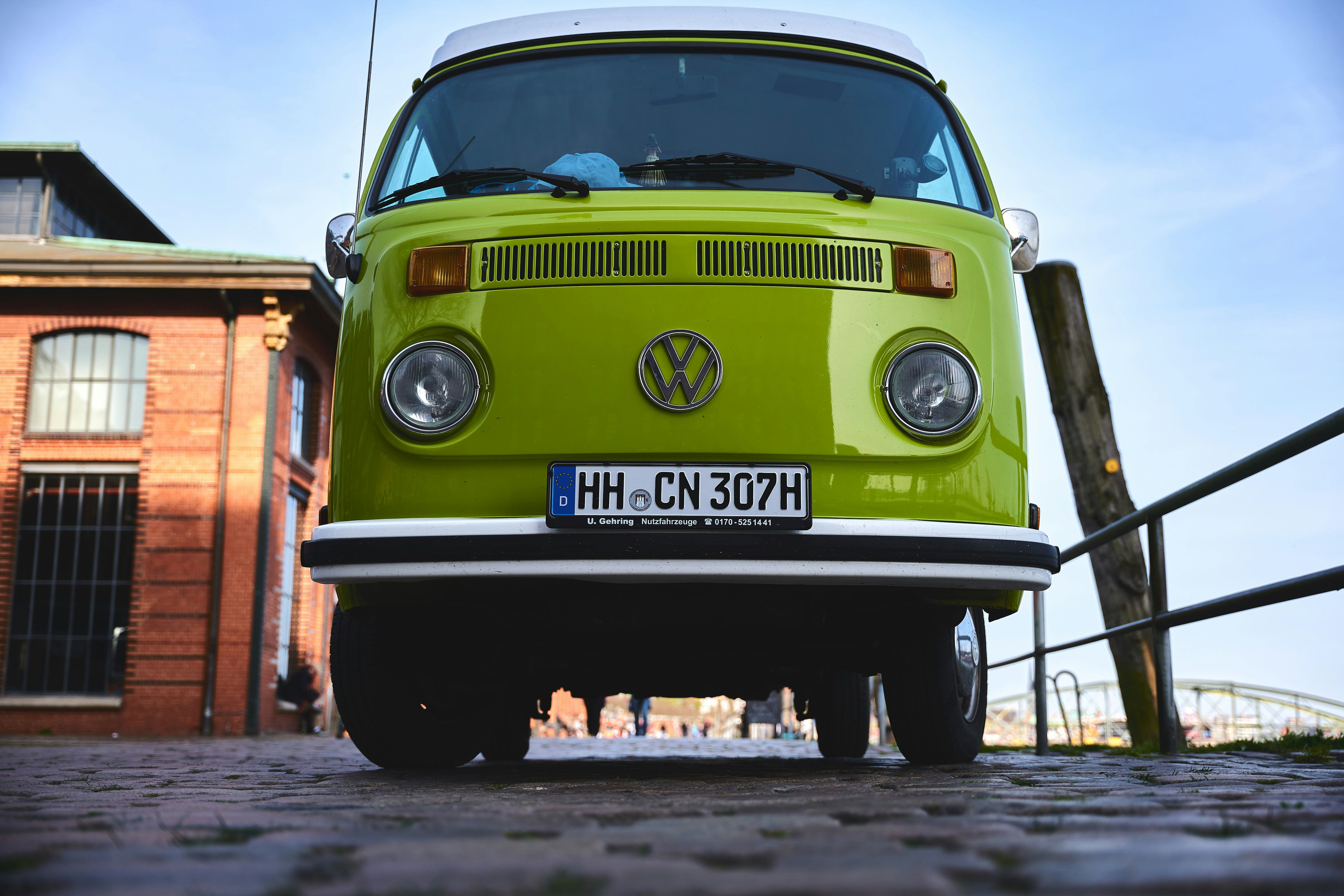 A green vw bus parked in front of a brick building photo – Free ...