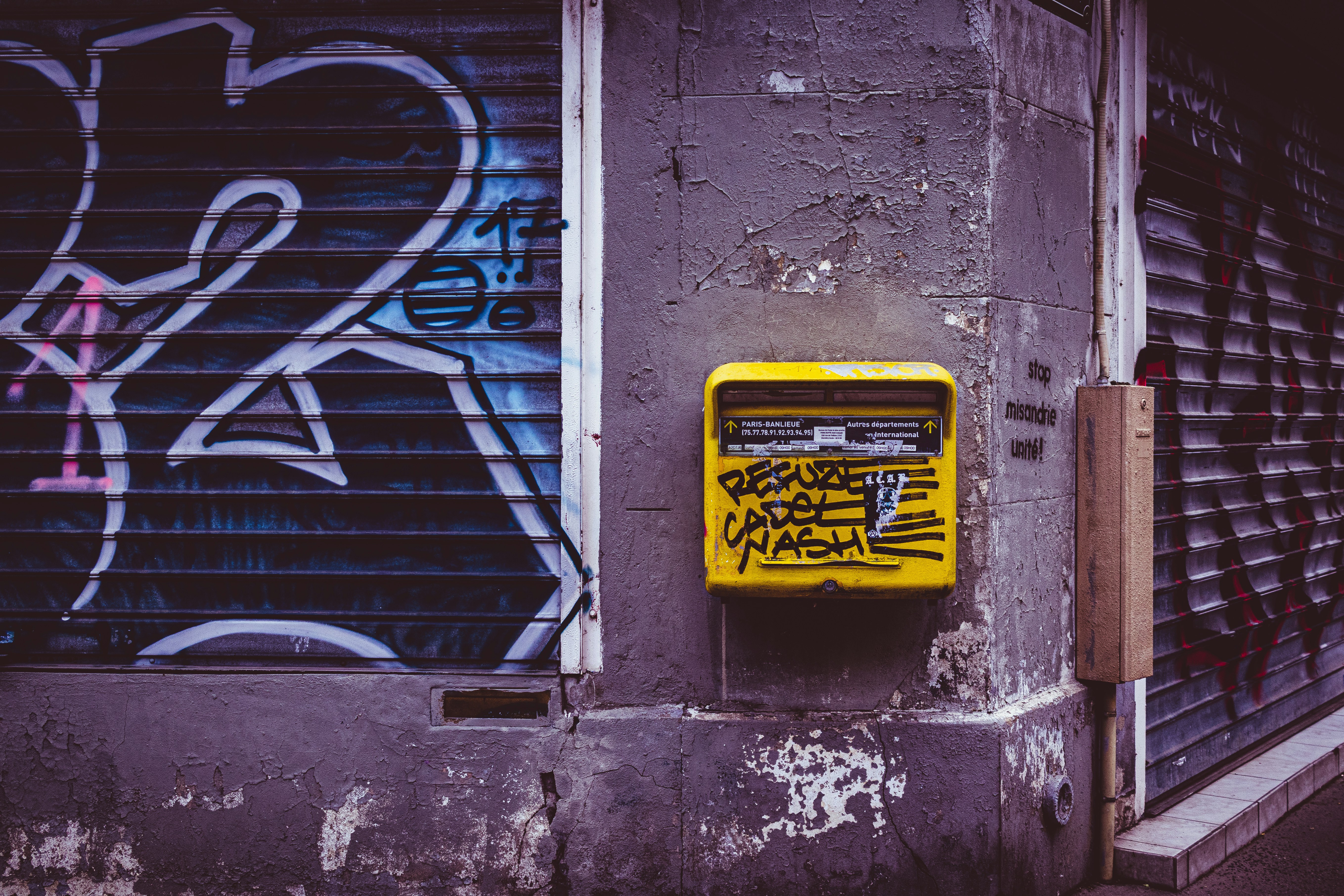 Yellow Mailbox on a Graffitied City Wall