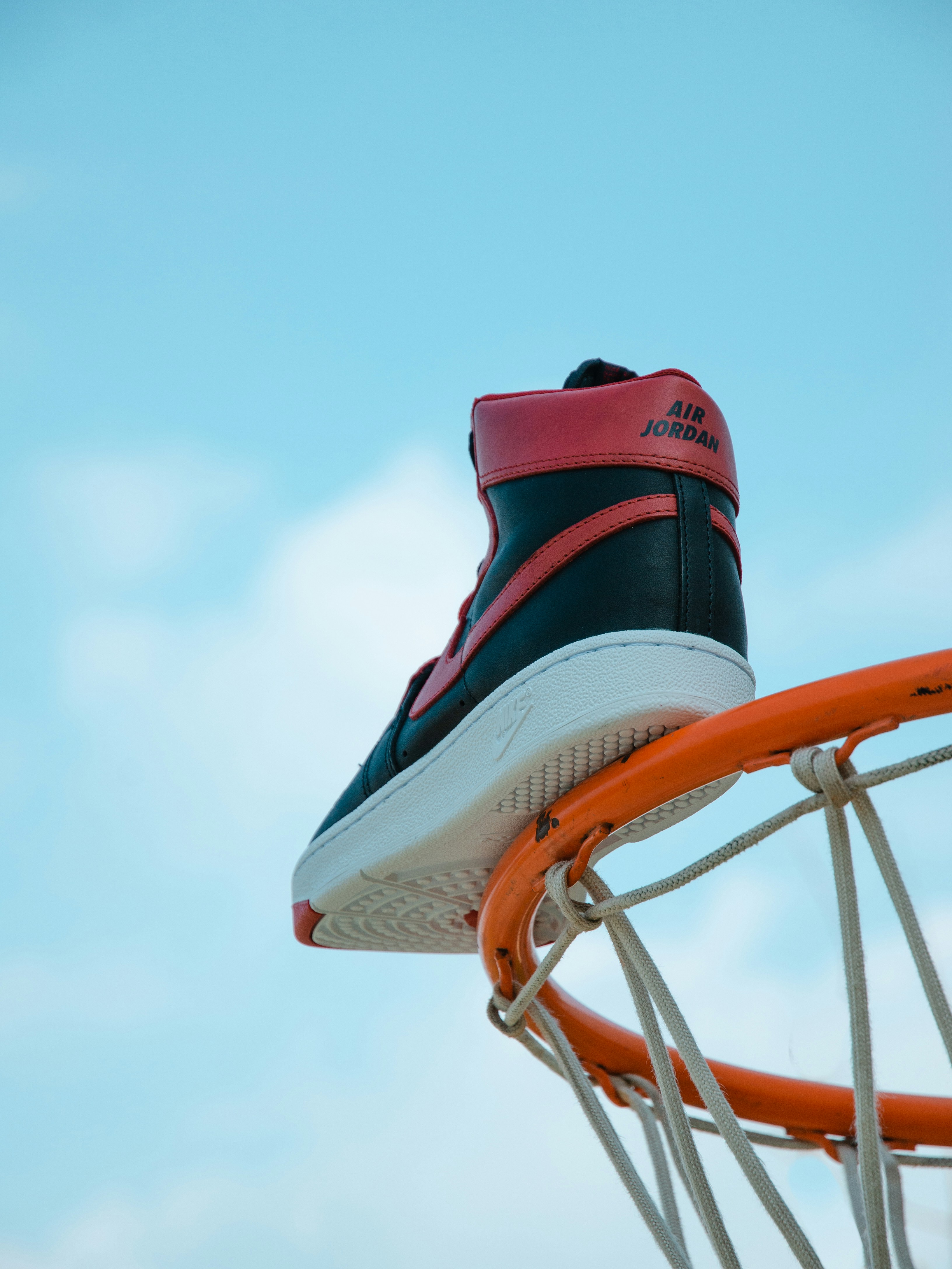 Air Jordan Ascends the Ring: a sneaker perched on a hoop beneath a clear blue sky