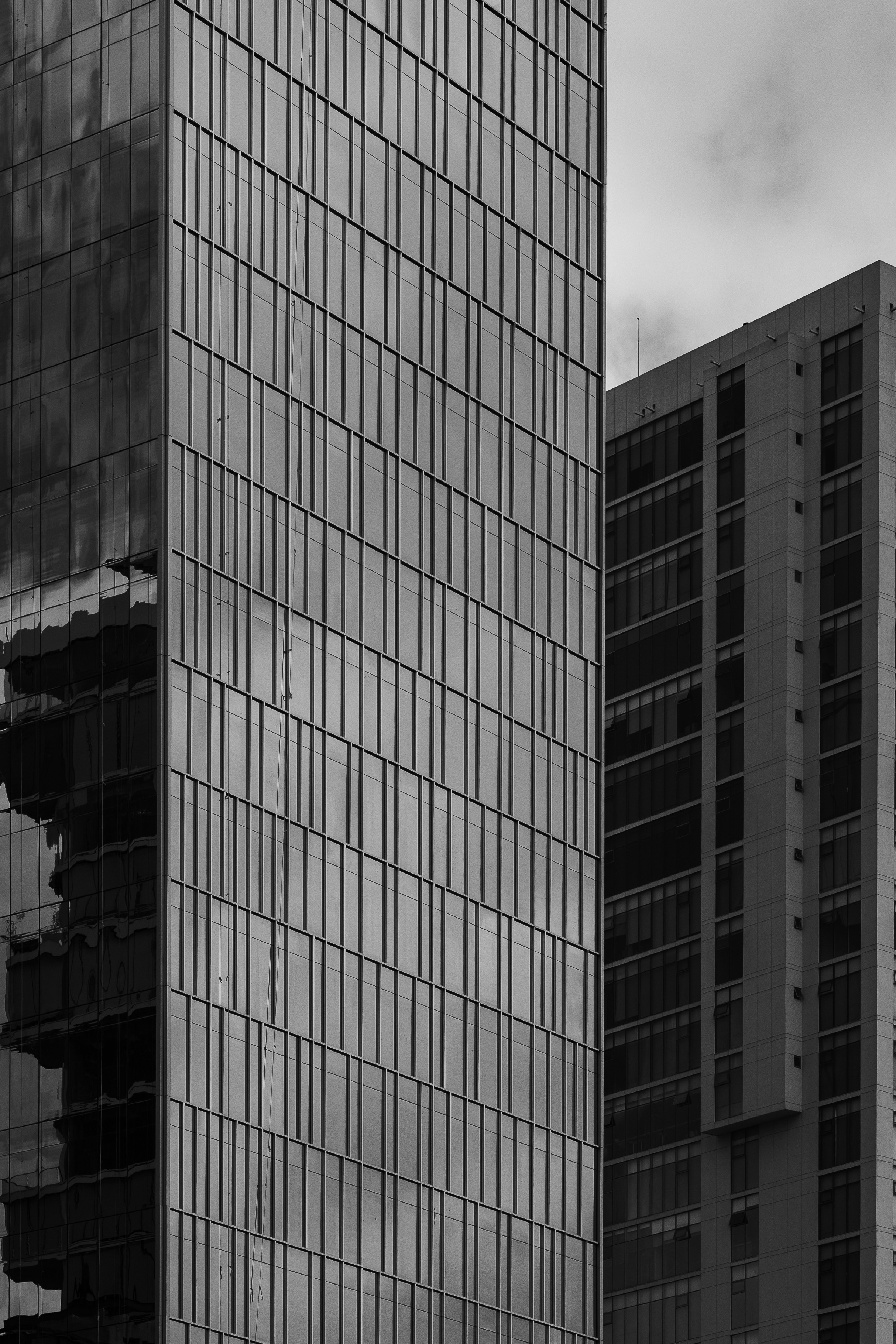 Abstract view of modern skyscraper facades reflecting clouds, emphasizing architectural lines and textures.