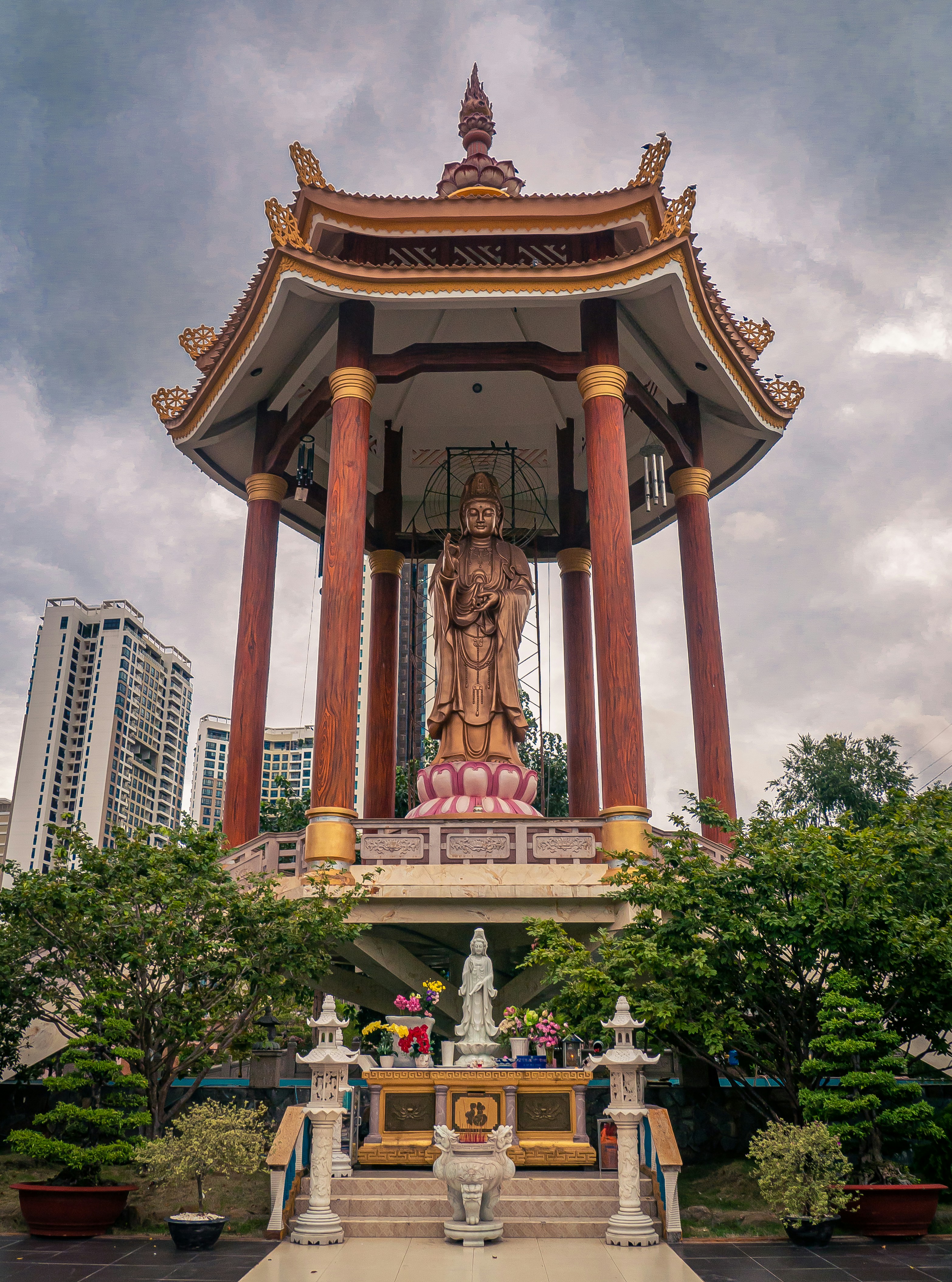 Gilded Buddha Under a Lofty Pavilion Amid Modern Skyscrapers