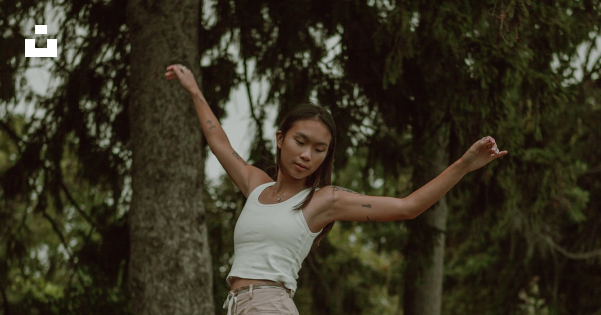 하얀 탱크 탑과 베이지색 바지를 입은 여자가 푸른 잔디밭에 서 있다 사진 Unsplash의 무료 사람의 이미지