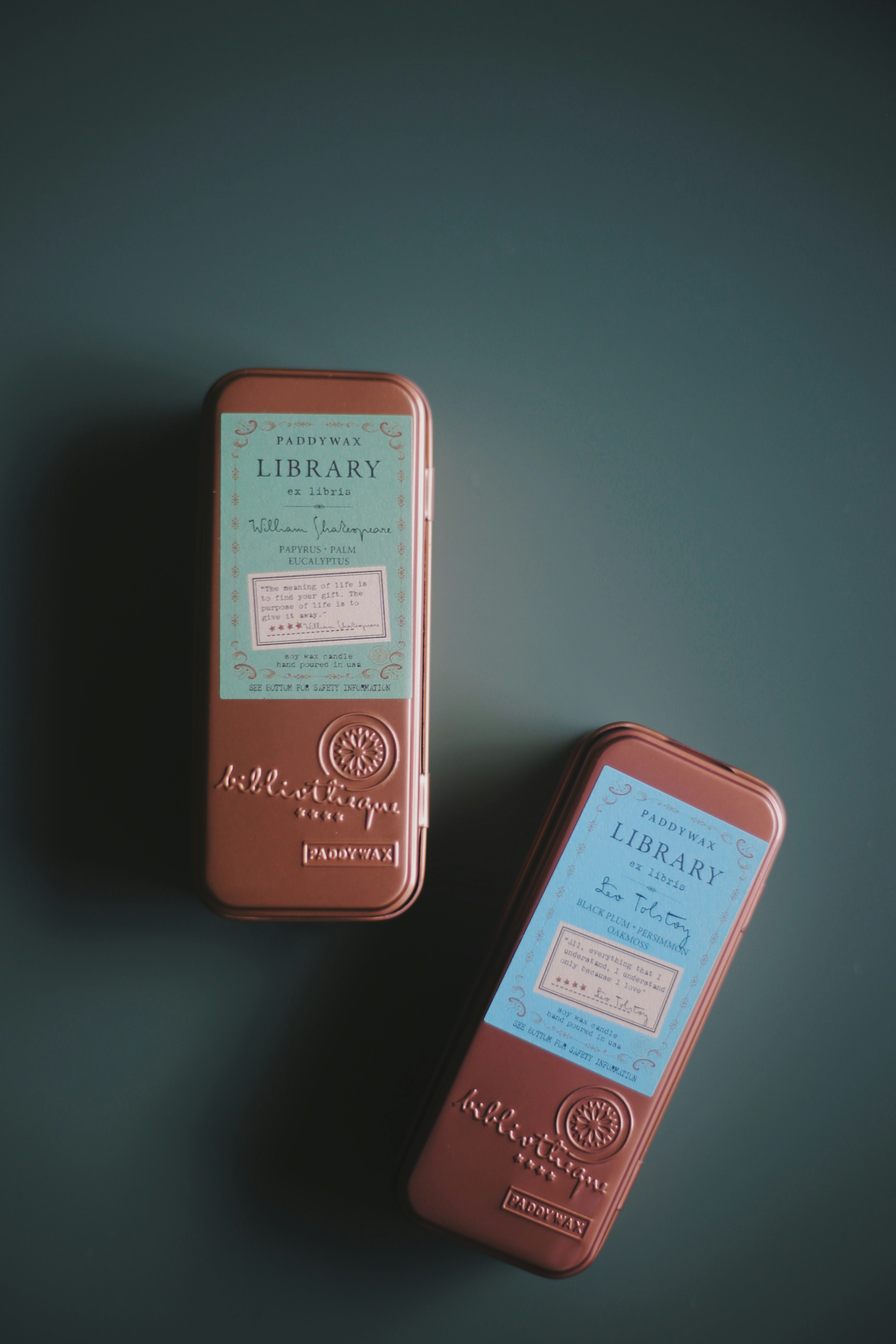 Two Vintage Library Tin Boxes Leaning on a Teal Backdrop