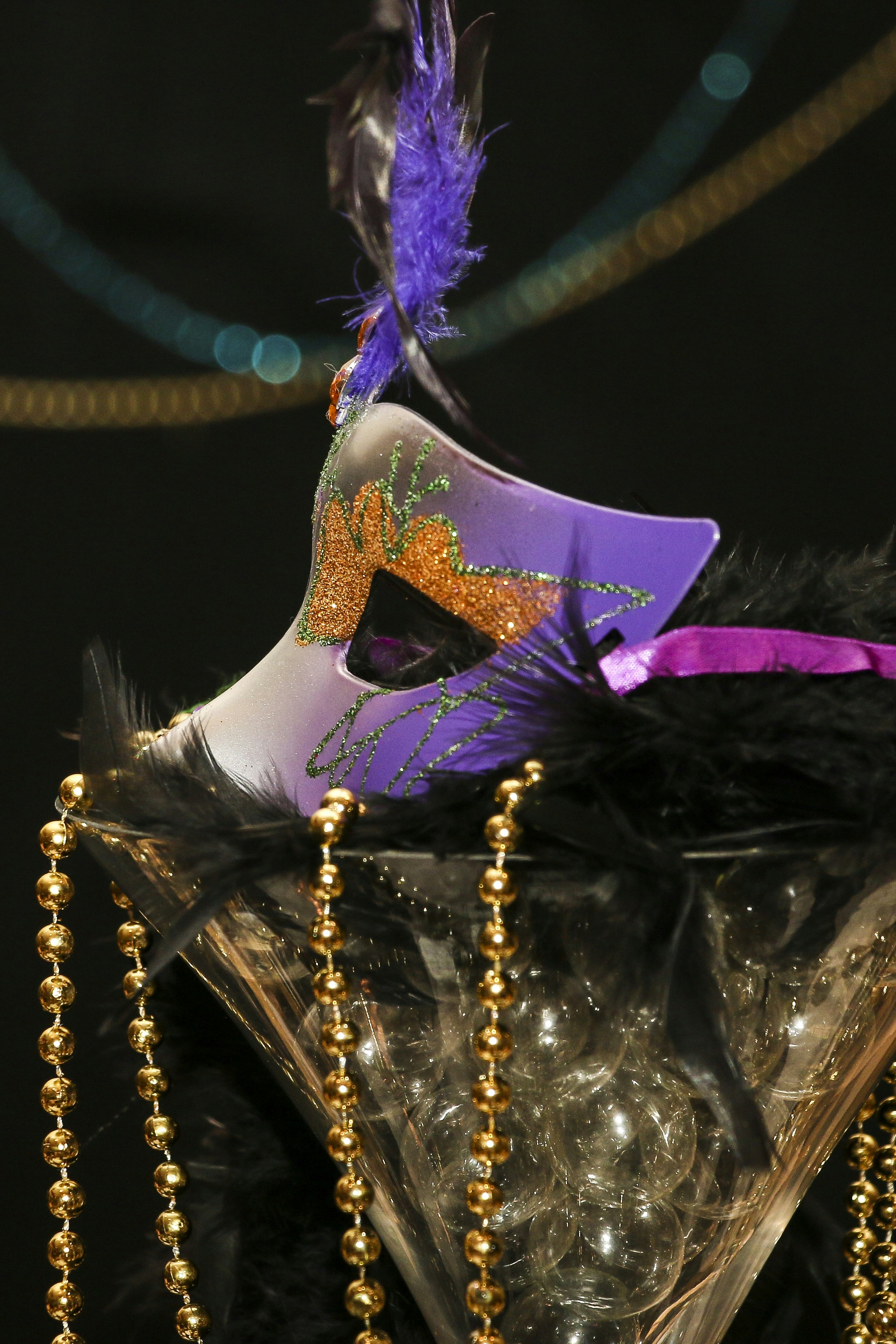 Glittering Carnival Mask Among Gold Beads and Black Feathers