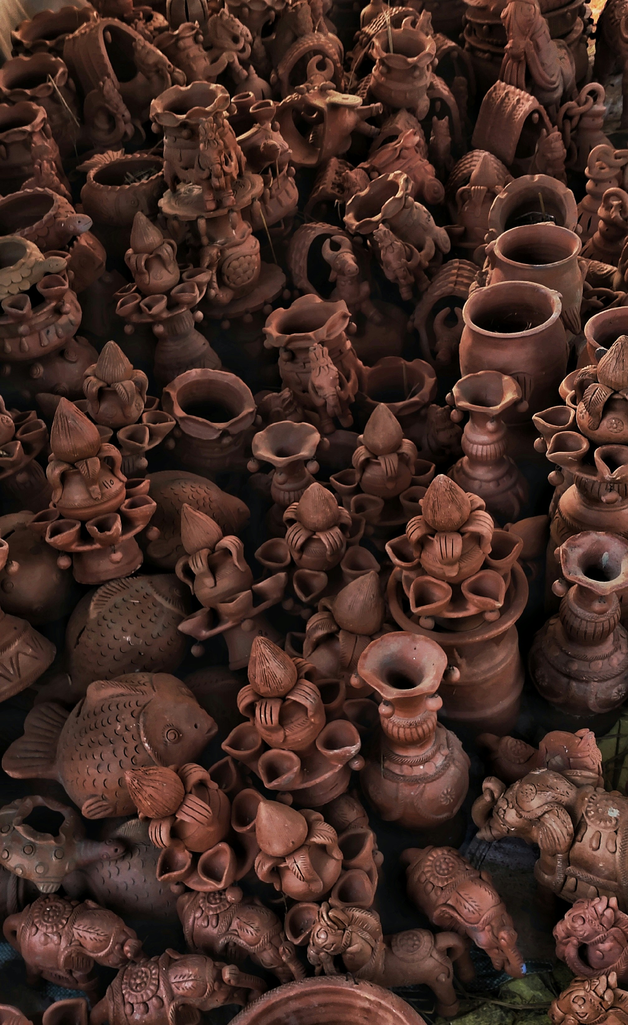 Dense field of terracotta pots and figurines packed tightly together, highlighting intricate textures and warm earthy tones.