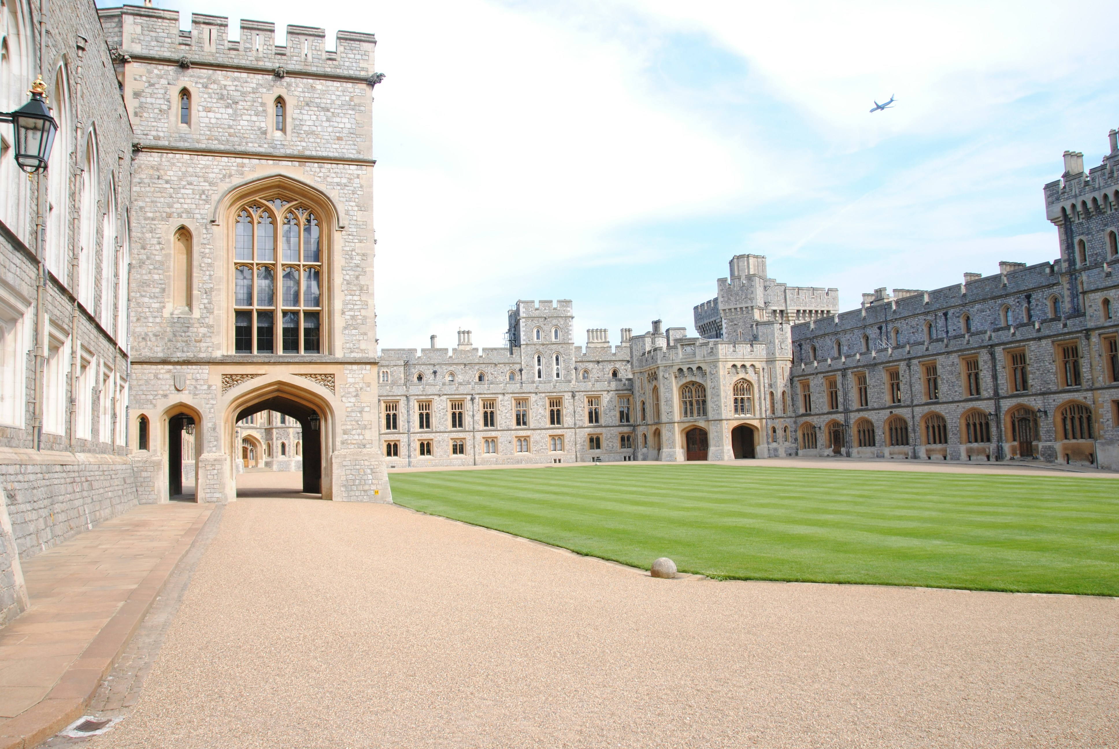 Historic castle courtyard framed by grand stone buildings under a clear sky.