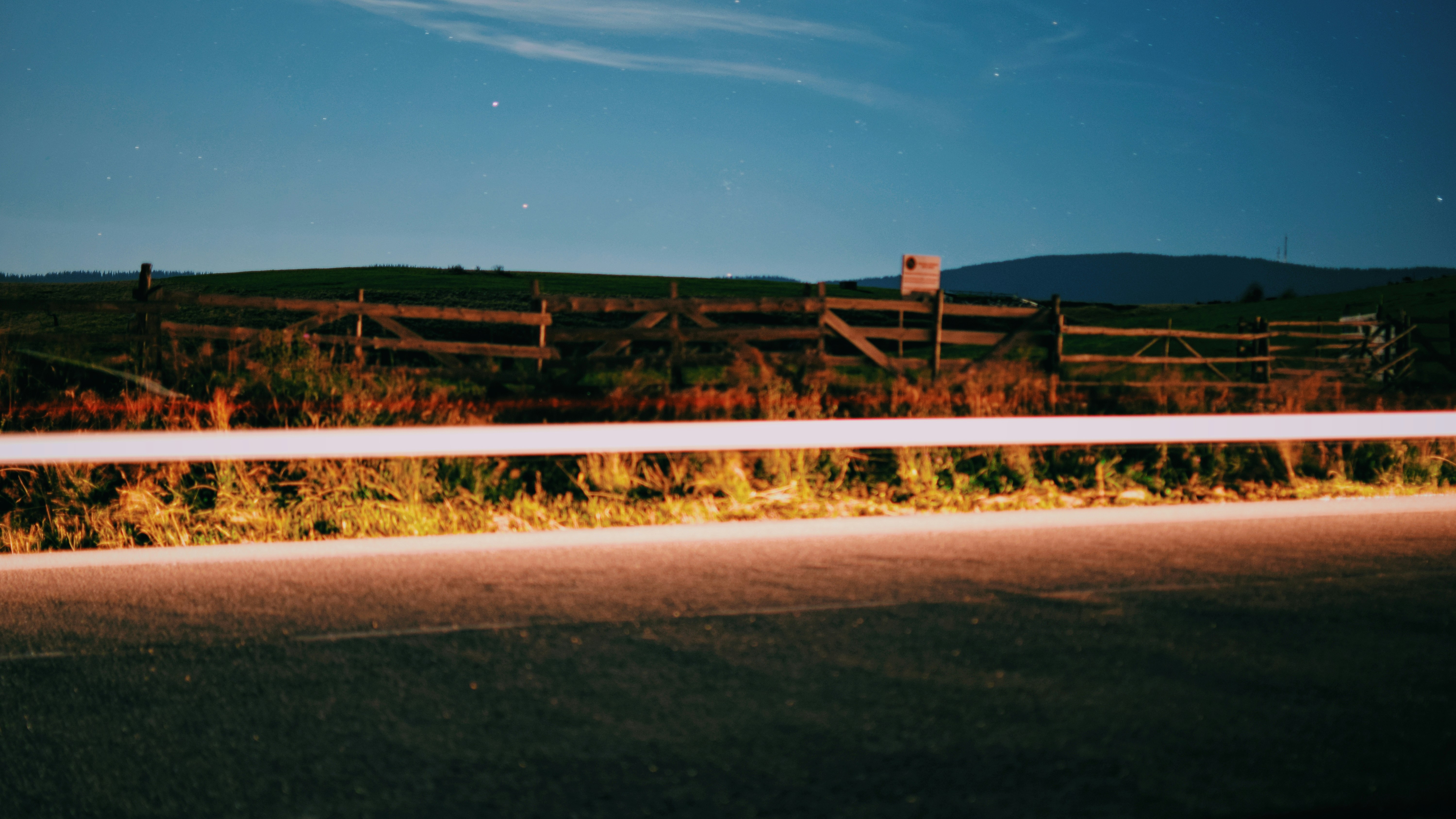 Dusk Verge: Weathered Fence Framing a Quiet Road
