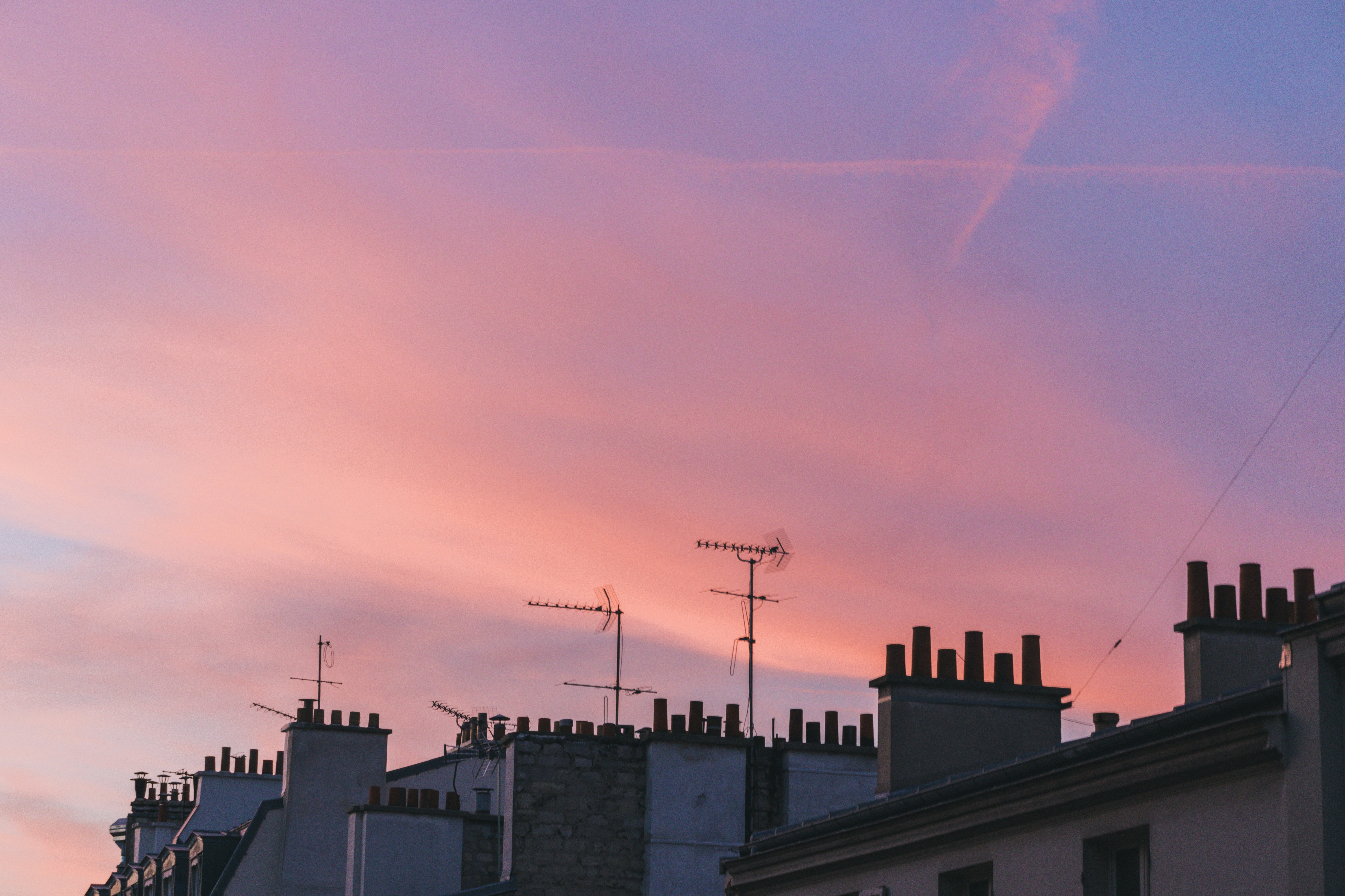 Pastel Rooftops: A Quiet Chorus of Antennas at Sunset
