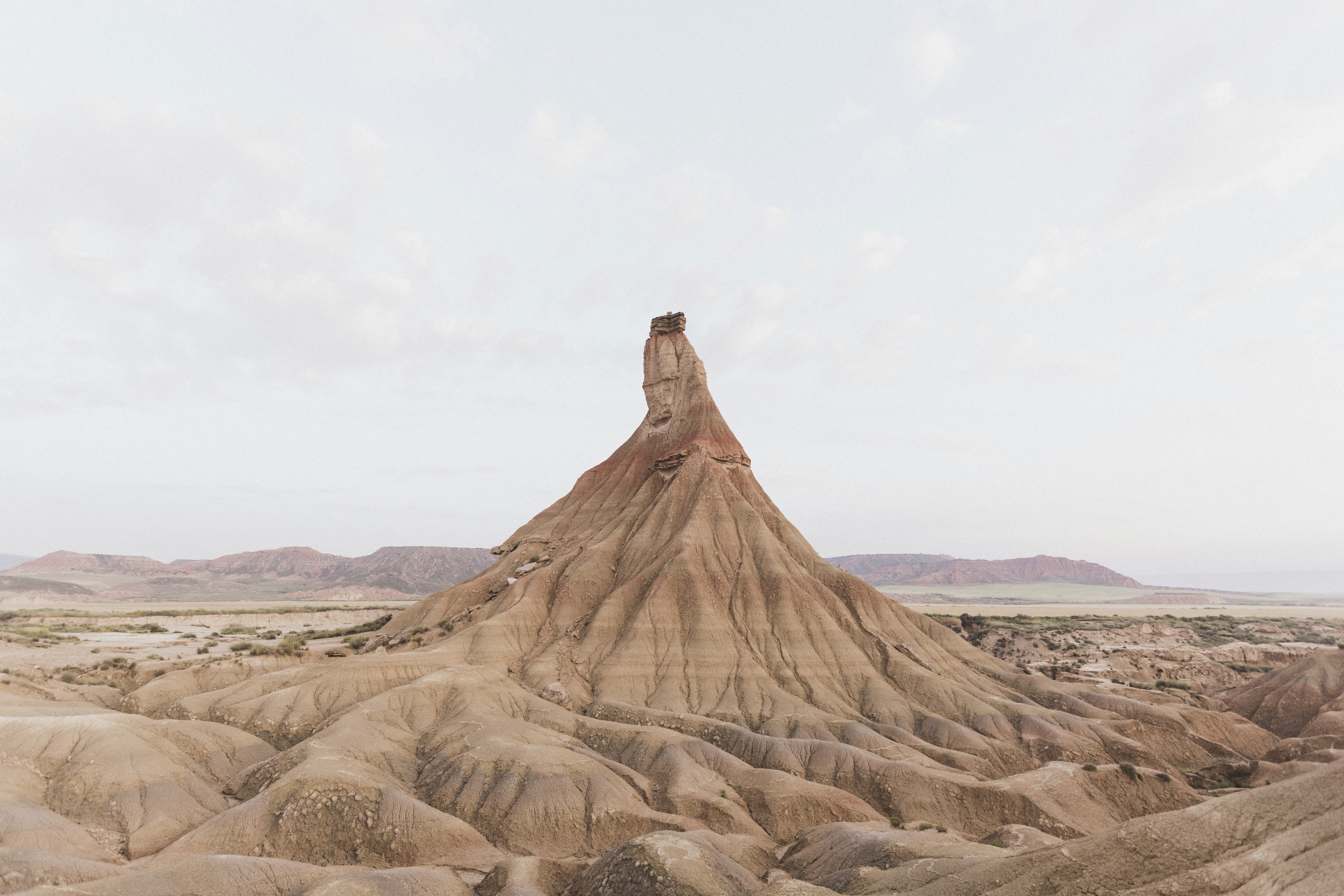 A dramatic rock formation towers above the arid landscape, showcasing the intricate patterns of erosion. The soft pastel sky adds a serene backdrop.