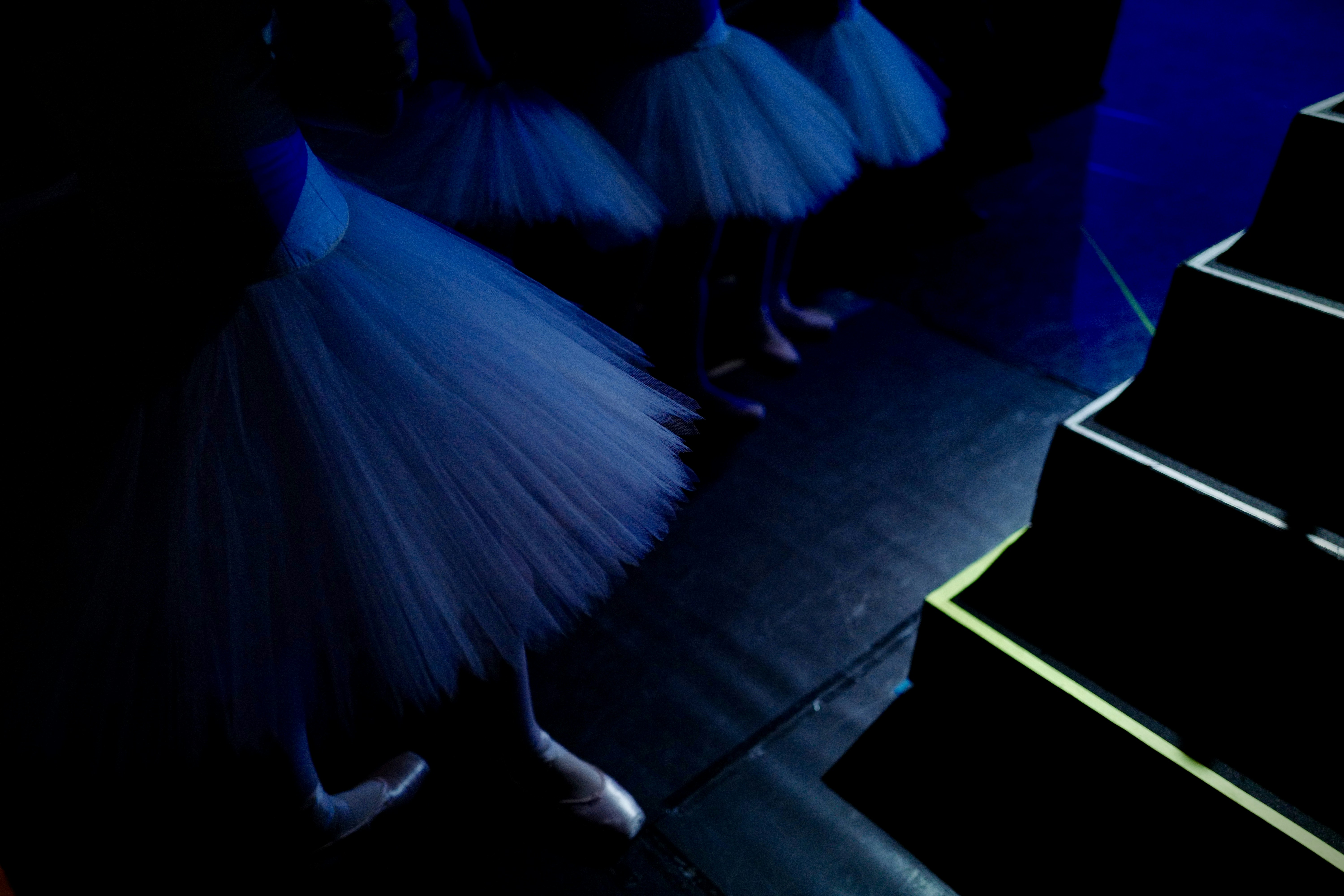 Cobalt hush: Blue tutu silhouettes on a neon-edged stage