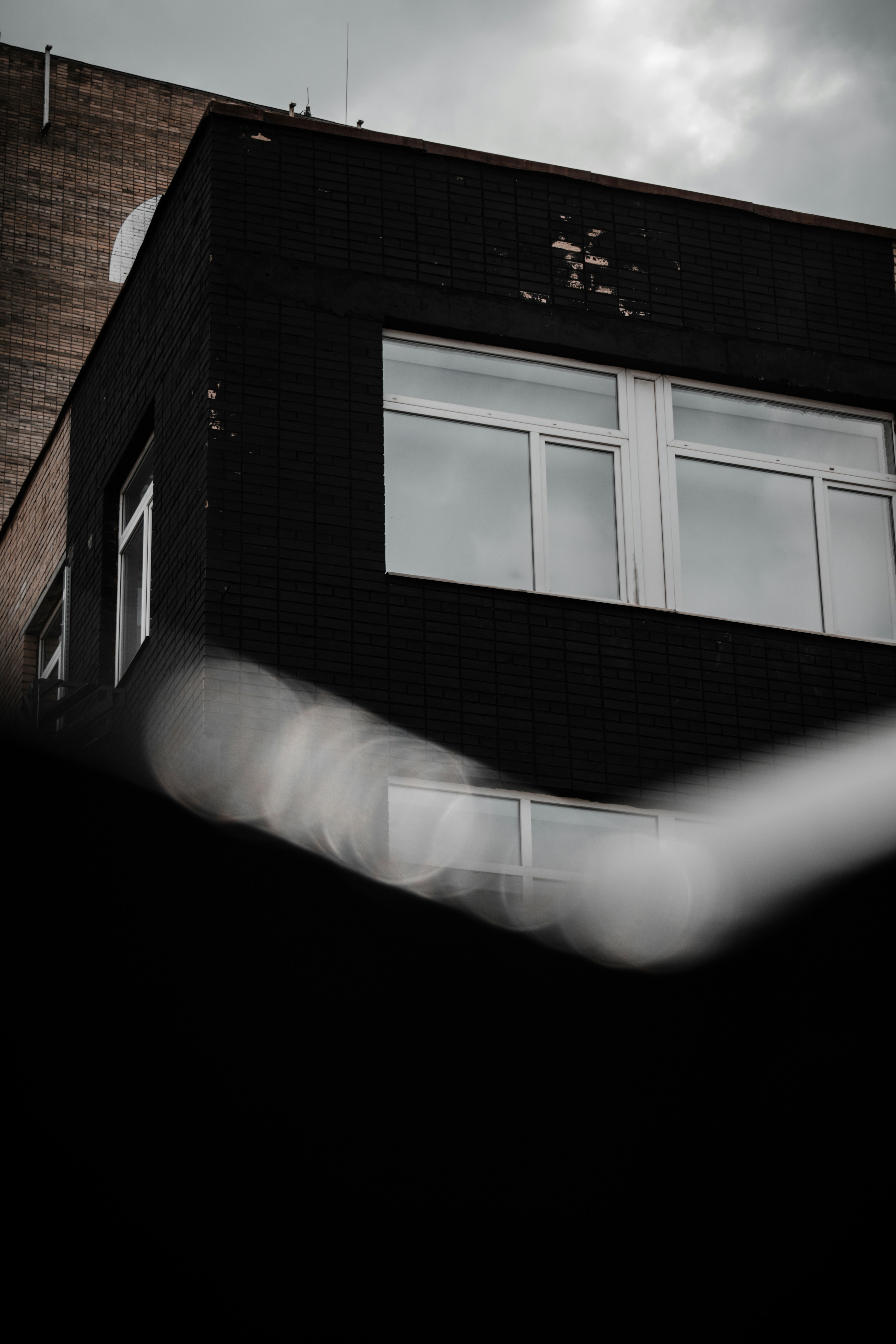 Edge of Darkness: Windowed Corner Against a Clouded Urban Sky