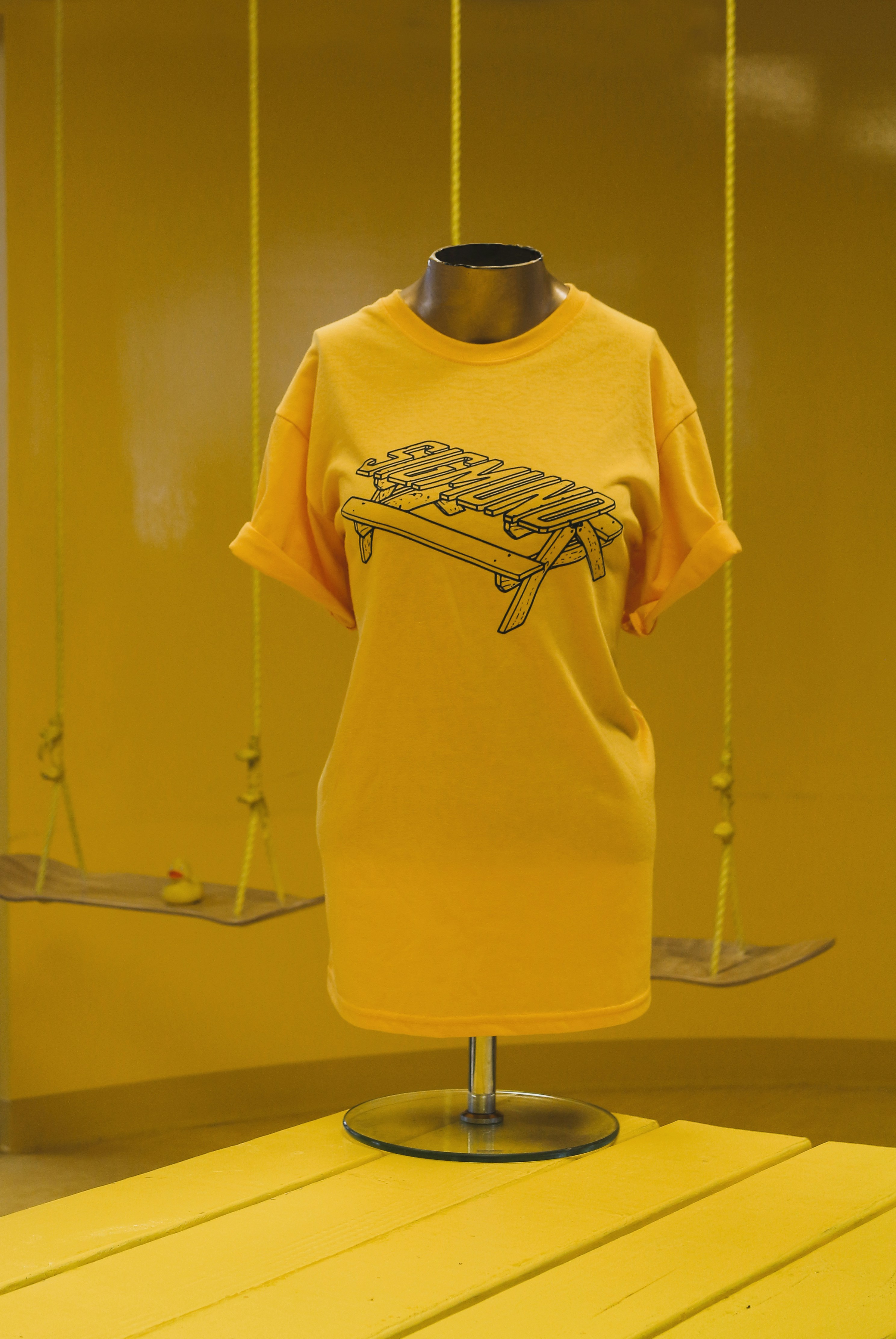 Canary Yellow Graphic Tee on a Stand in a Bright Rope-Swing Studio