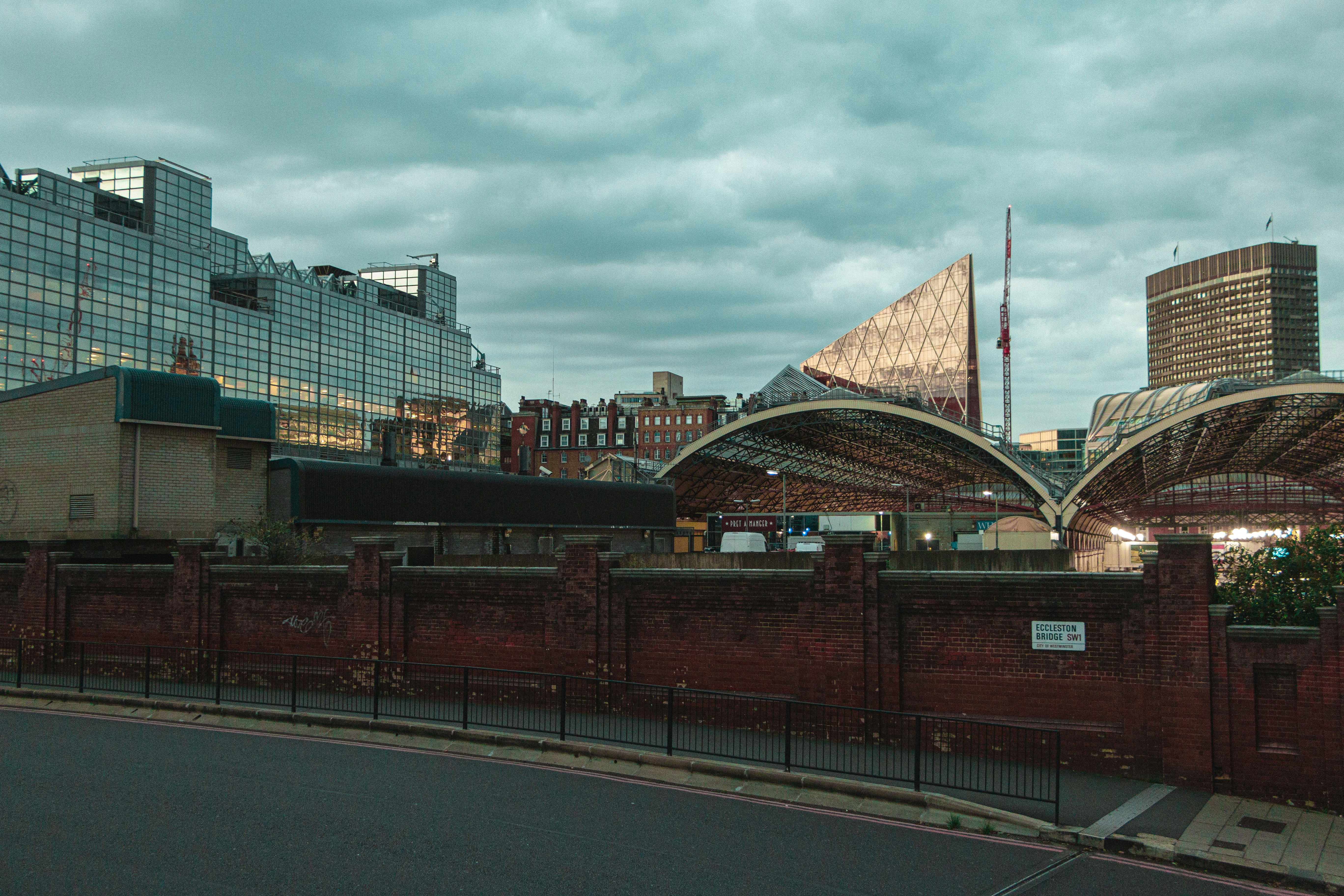 Modern architectural structures reflect the changing sky, showcasing a blend of glass and steel designs in an urban setting.