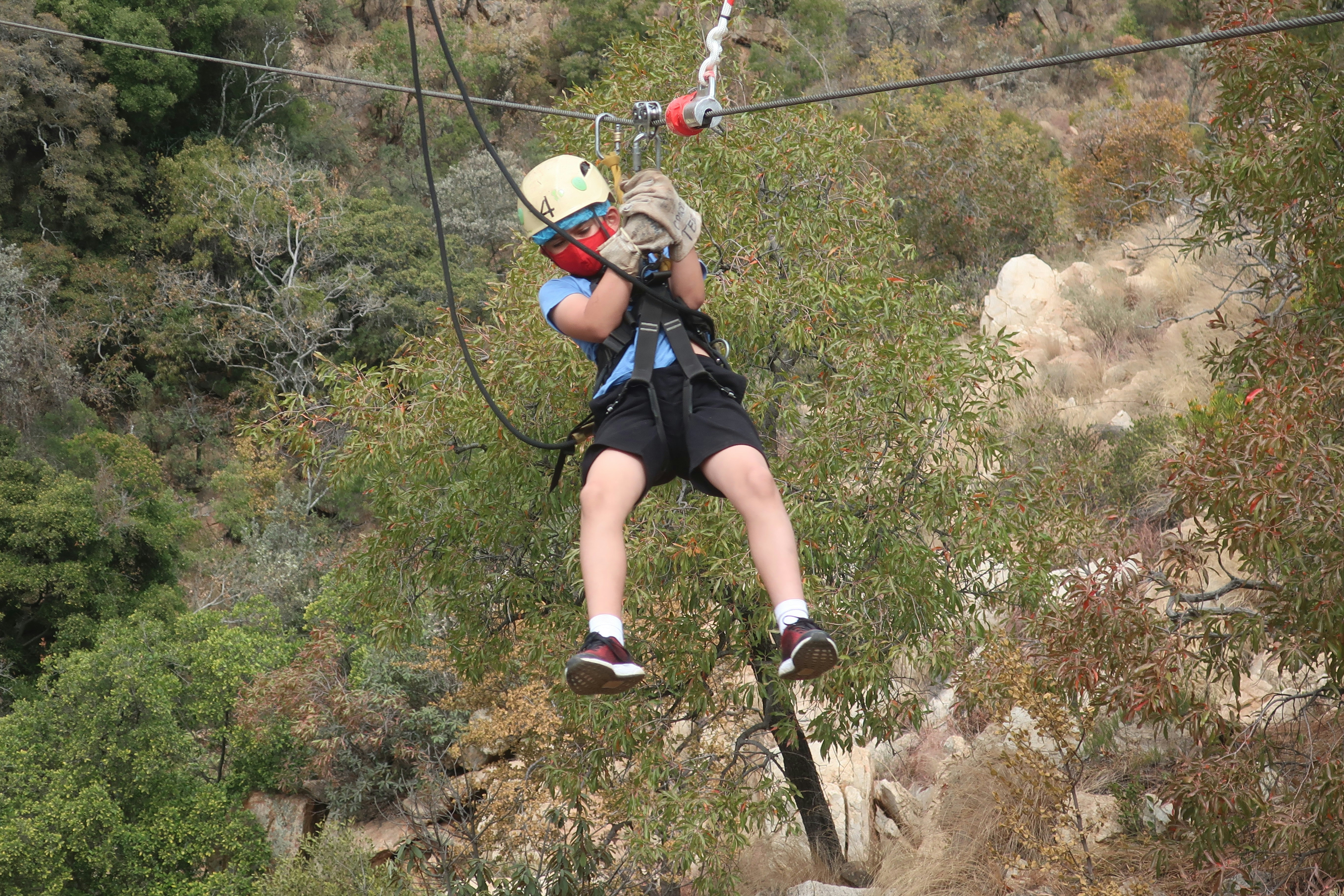 woman in blue shorts and white helmet climbing on mountain during daytime