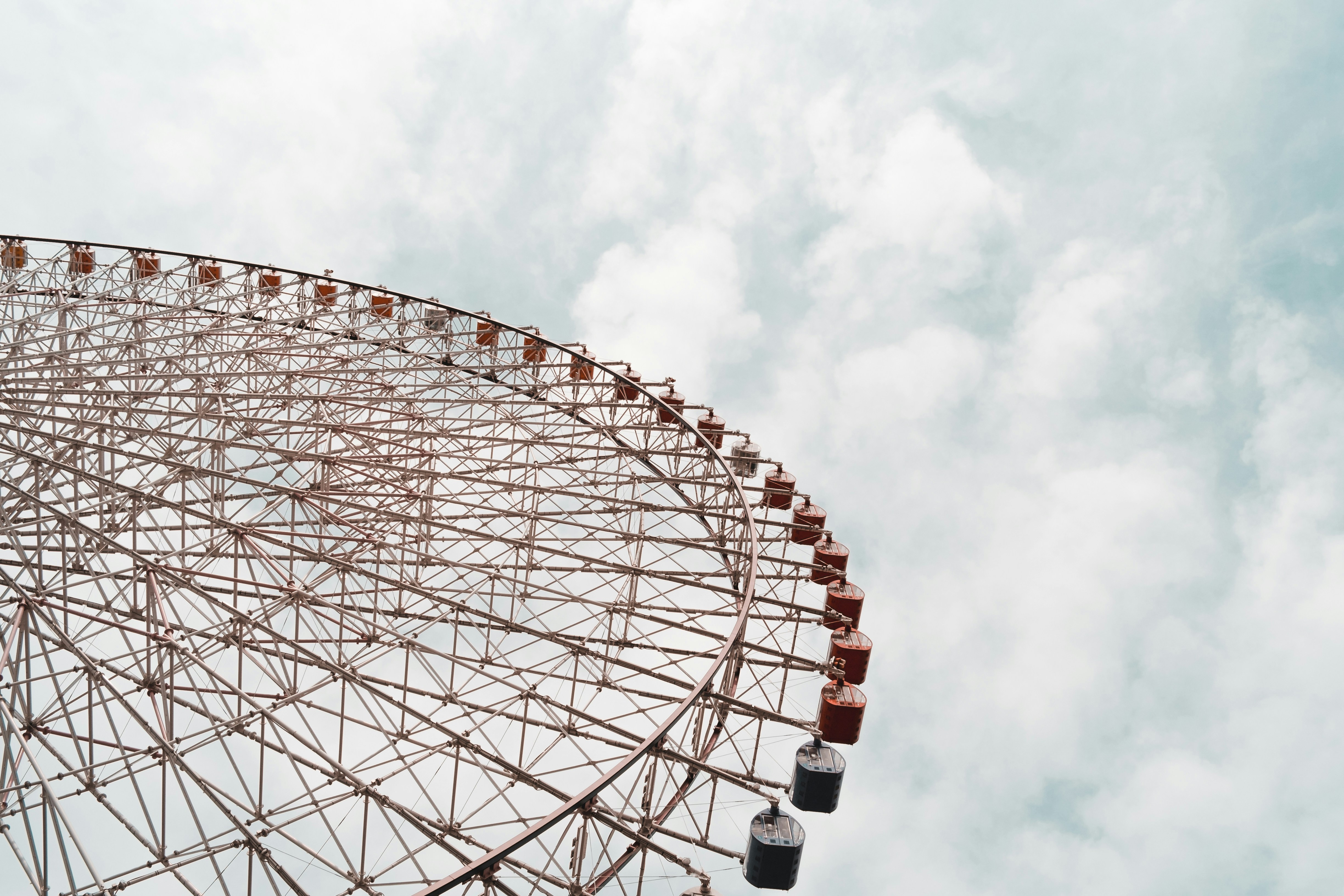 A towering Ferris wheel stands against a backdrop of soft, cloudy skies, showcasing its intricate structure and colorful cabins.