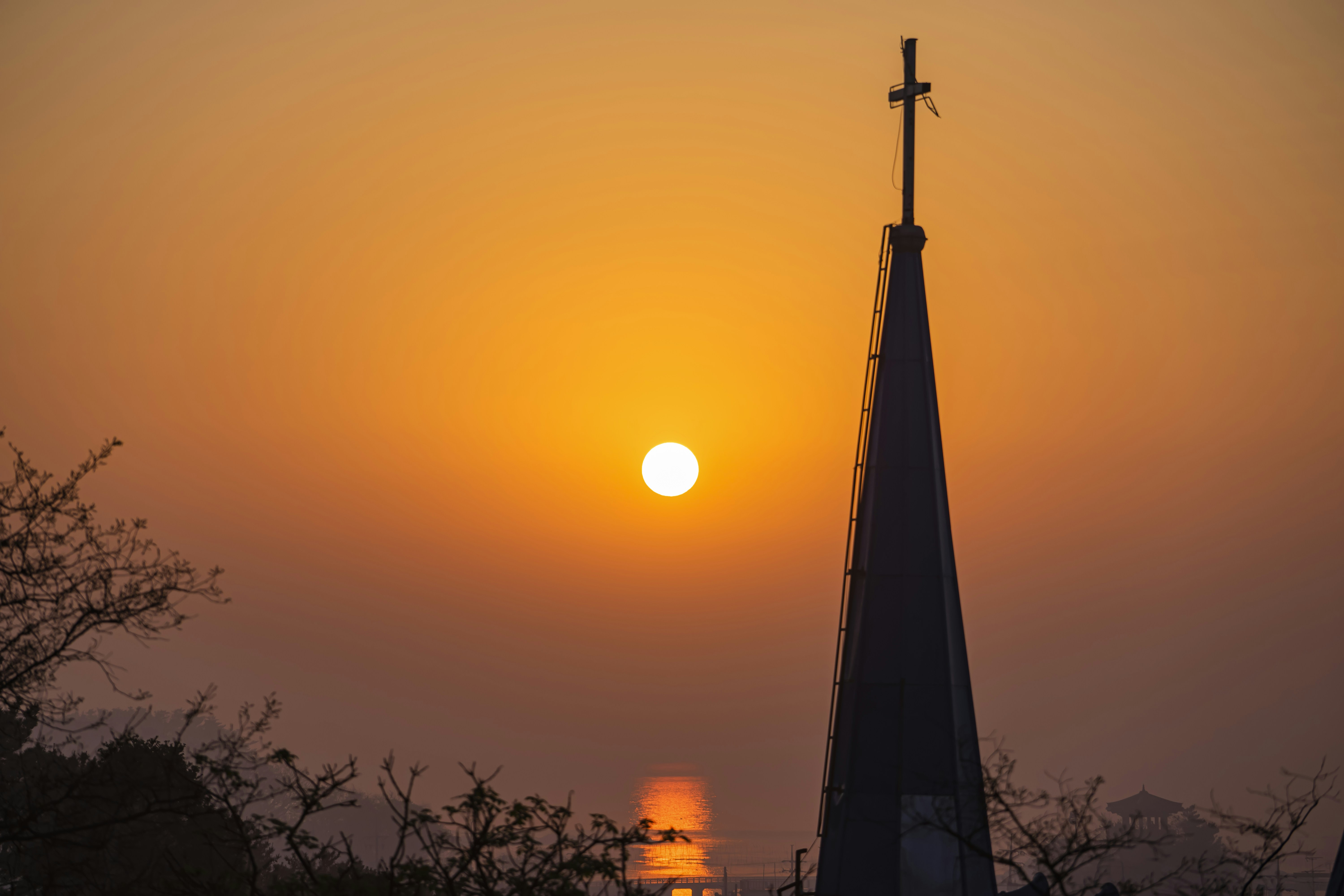 Sunlit Spire at Dusk: A Quiet Waterfront Silhouette