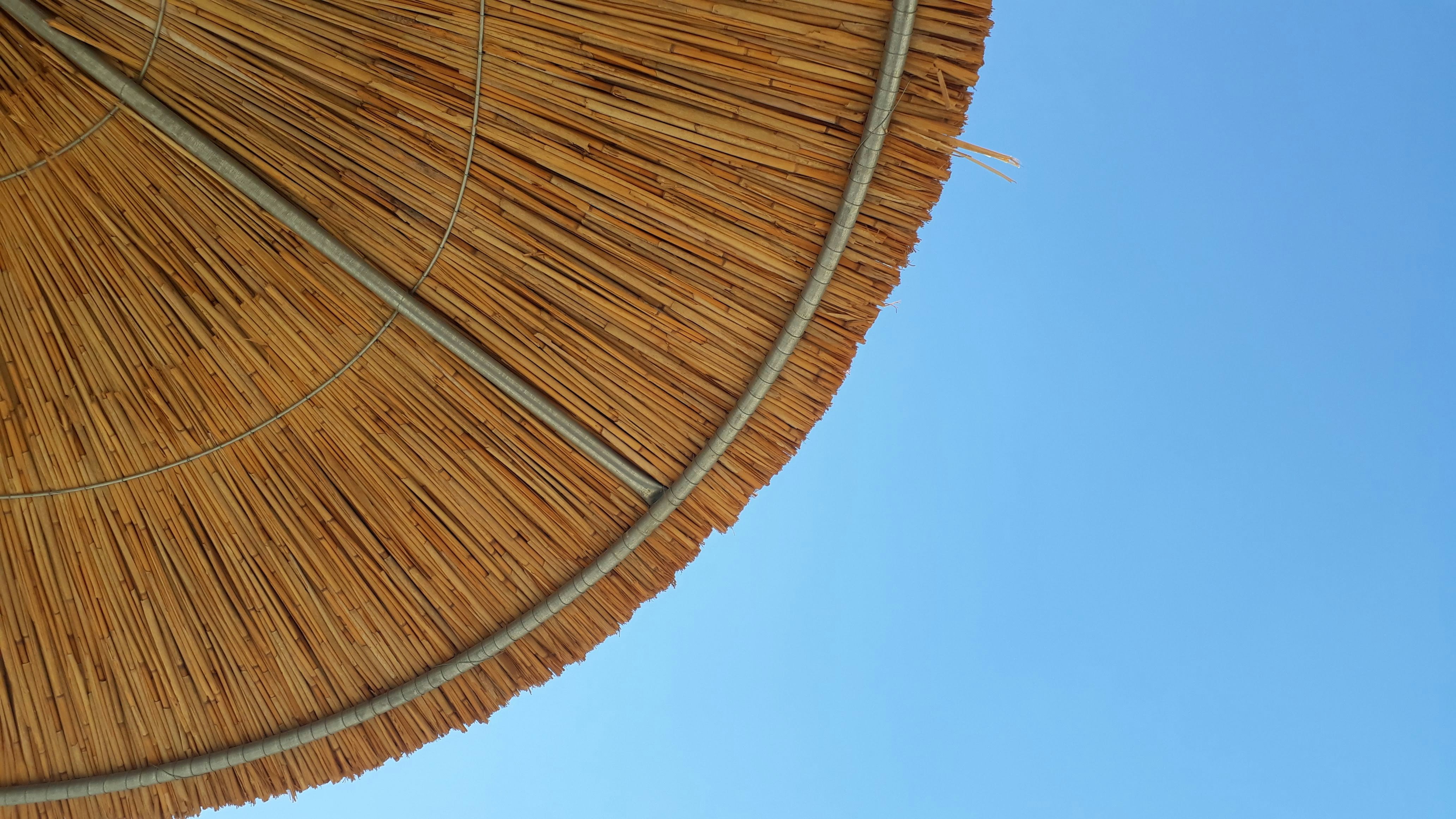 Straw umbrella against a clear blue sky on a sunny day.