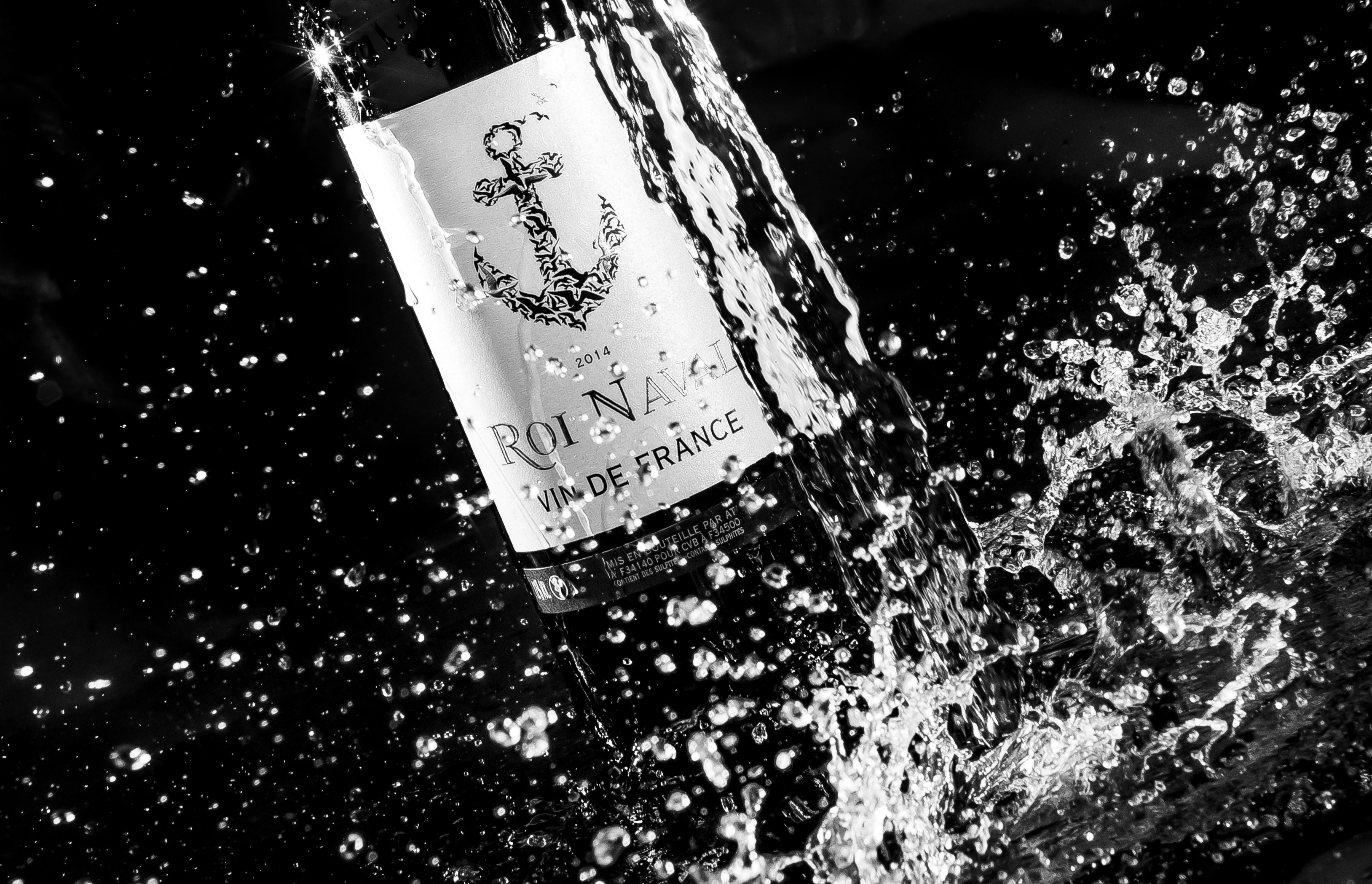 Wine bottle splashing through water, showcasing dynamic movement and fluidity in a monochromatic setting.