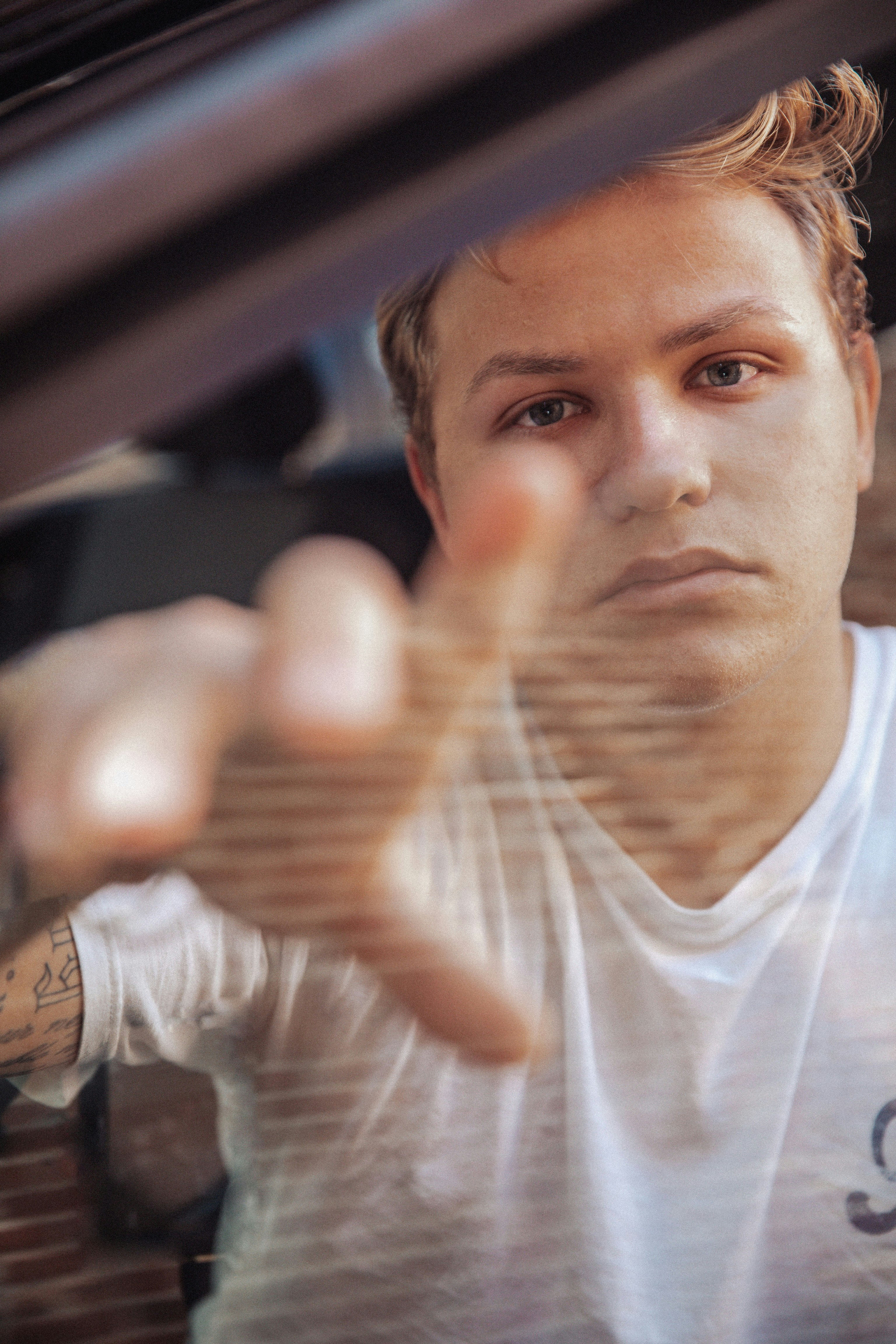 Young man reaching out through a car window, with a contemplative expression. The scene captures a moment of introspection and connection.