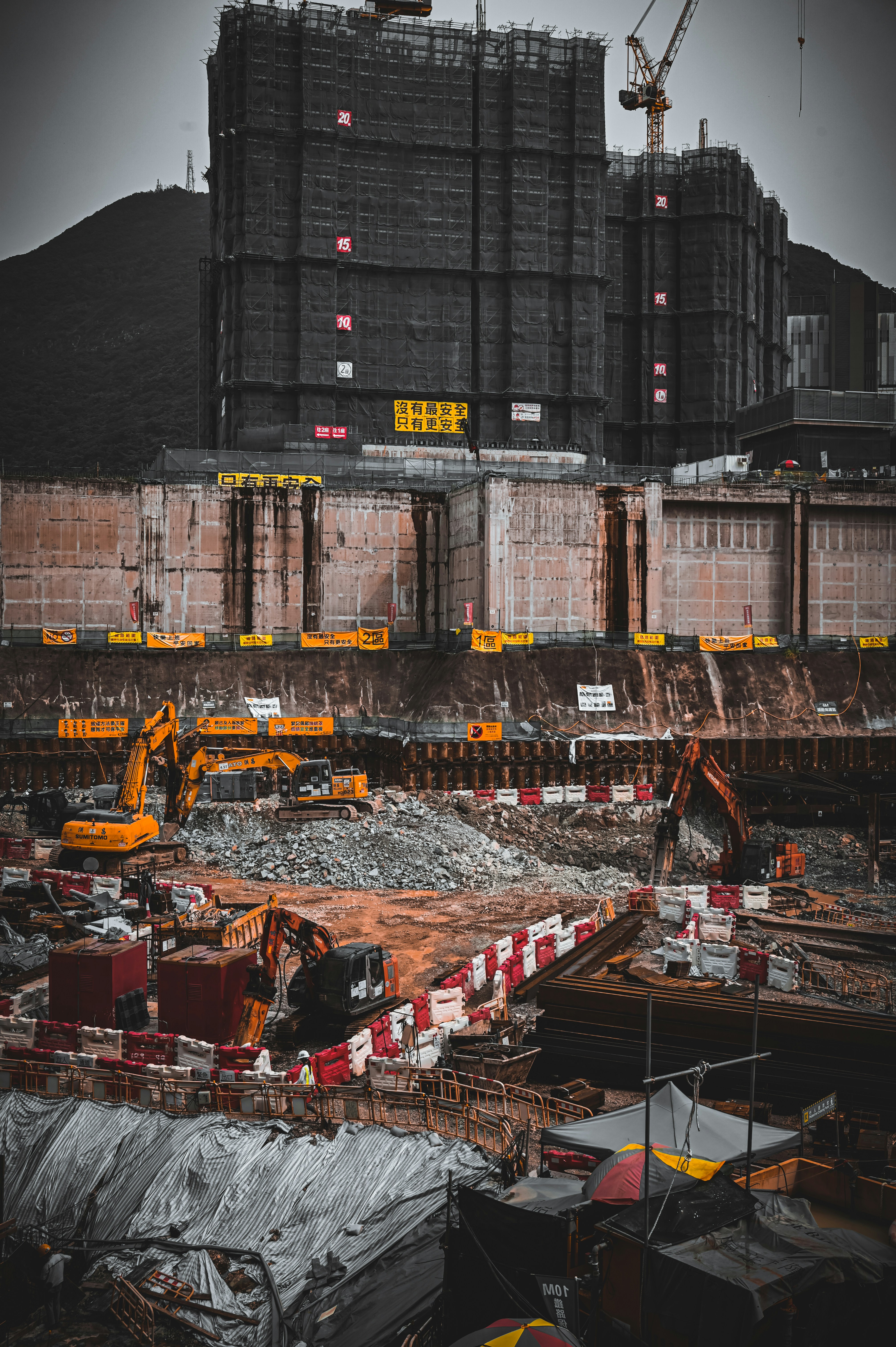 Heavy machinery at a construction site surrounded by scaffolding and debris, showcasing the dynamic process of urban development.
