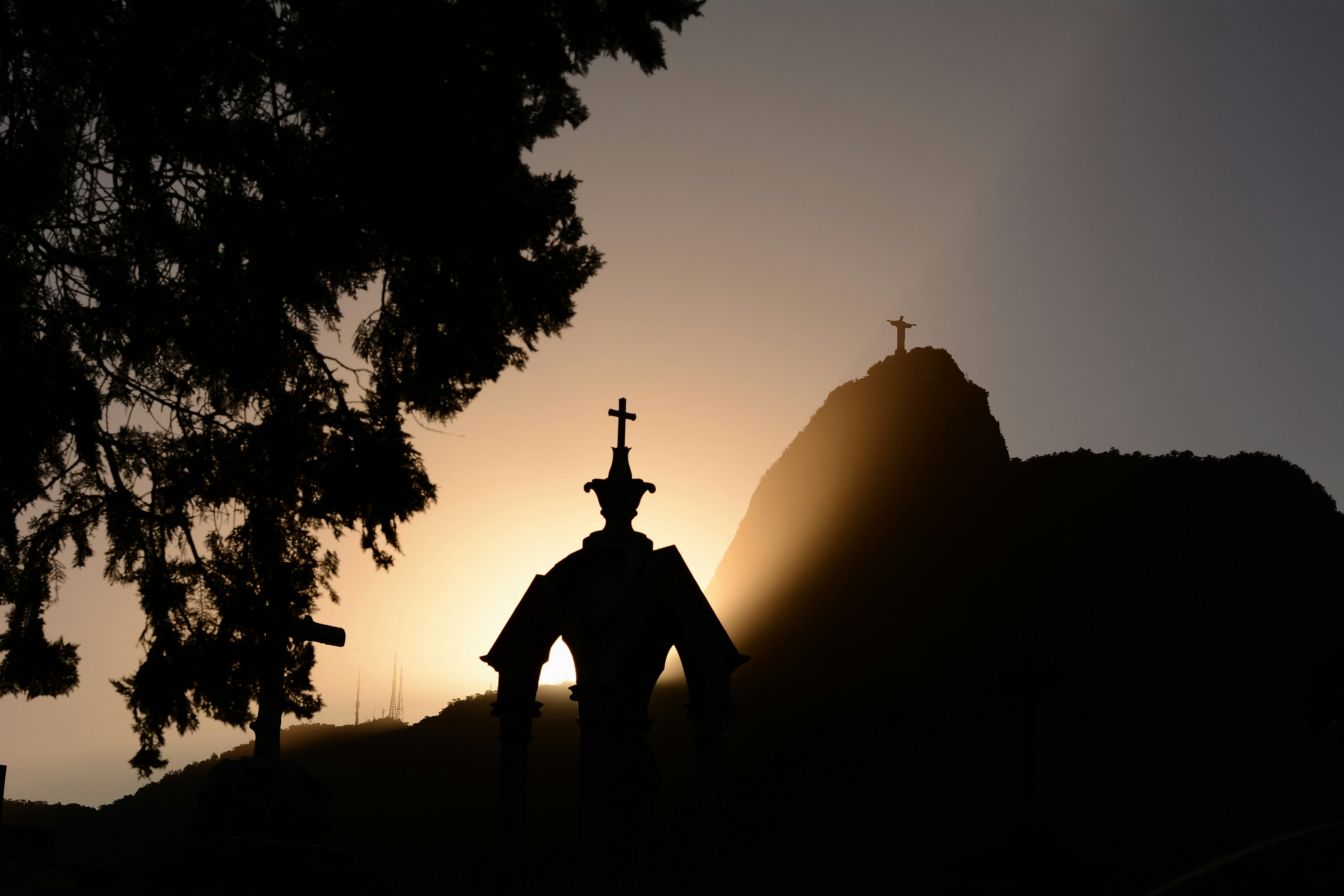 Silhouettes of crosses against a glowing sunset, highlighting the spiritual ambiance of the scene.