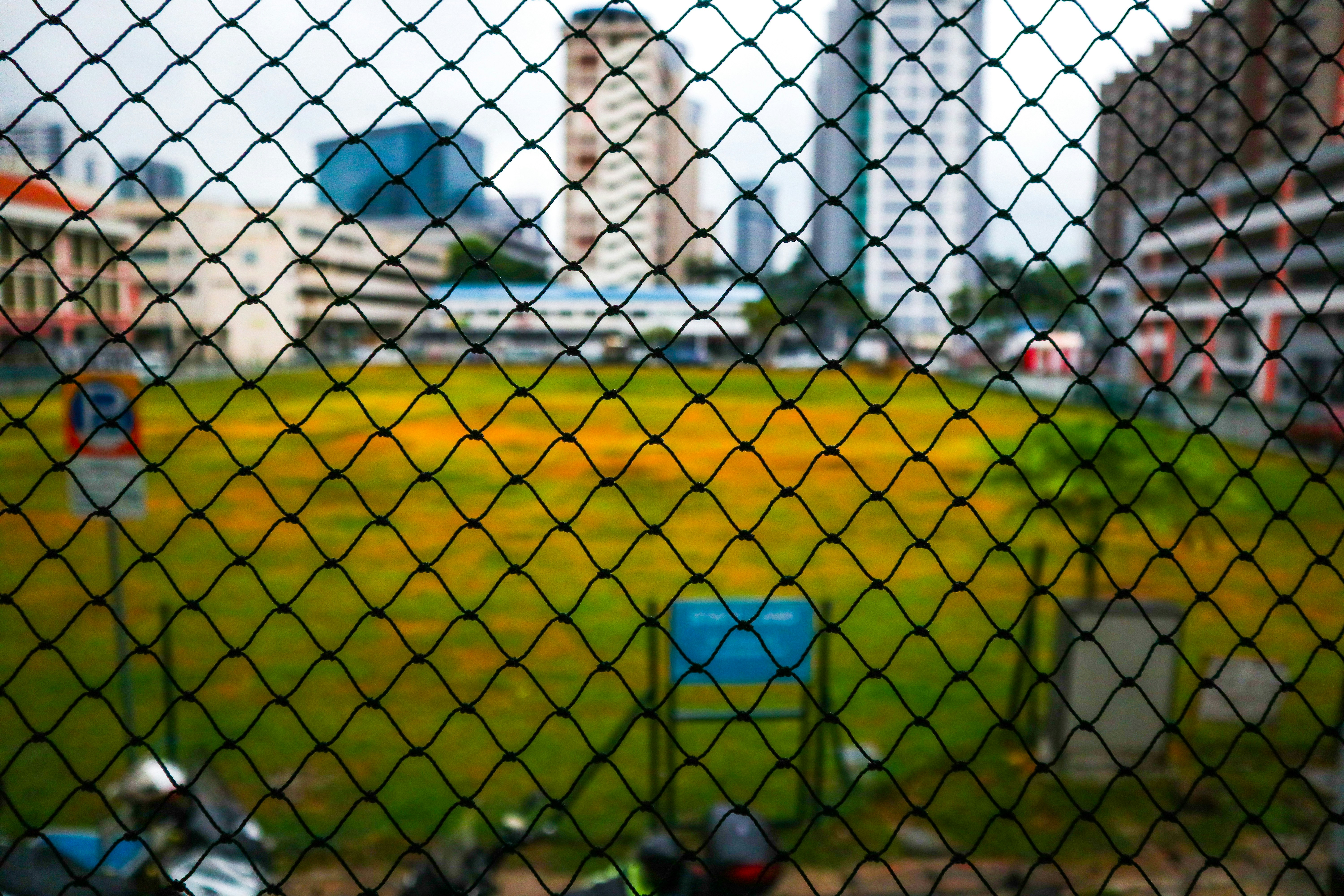 blue plastic trash bin beside gray metal fence