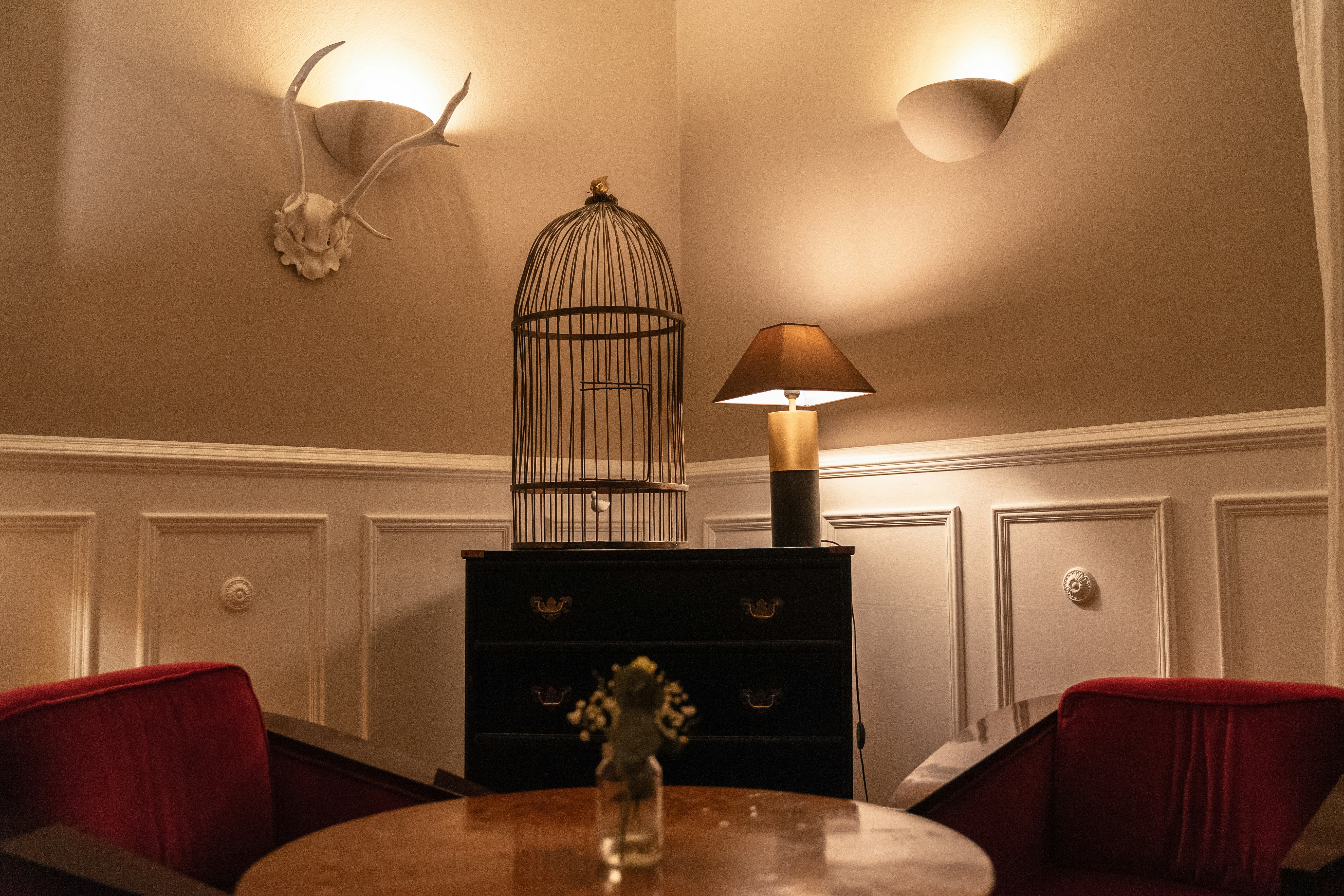 Dim Parlor Chorus: A Quiet Corner with a Birdcage and Candlelight