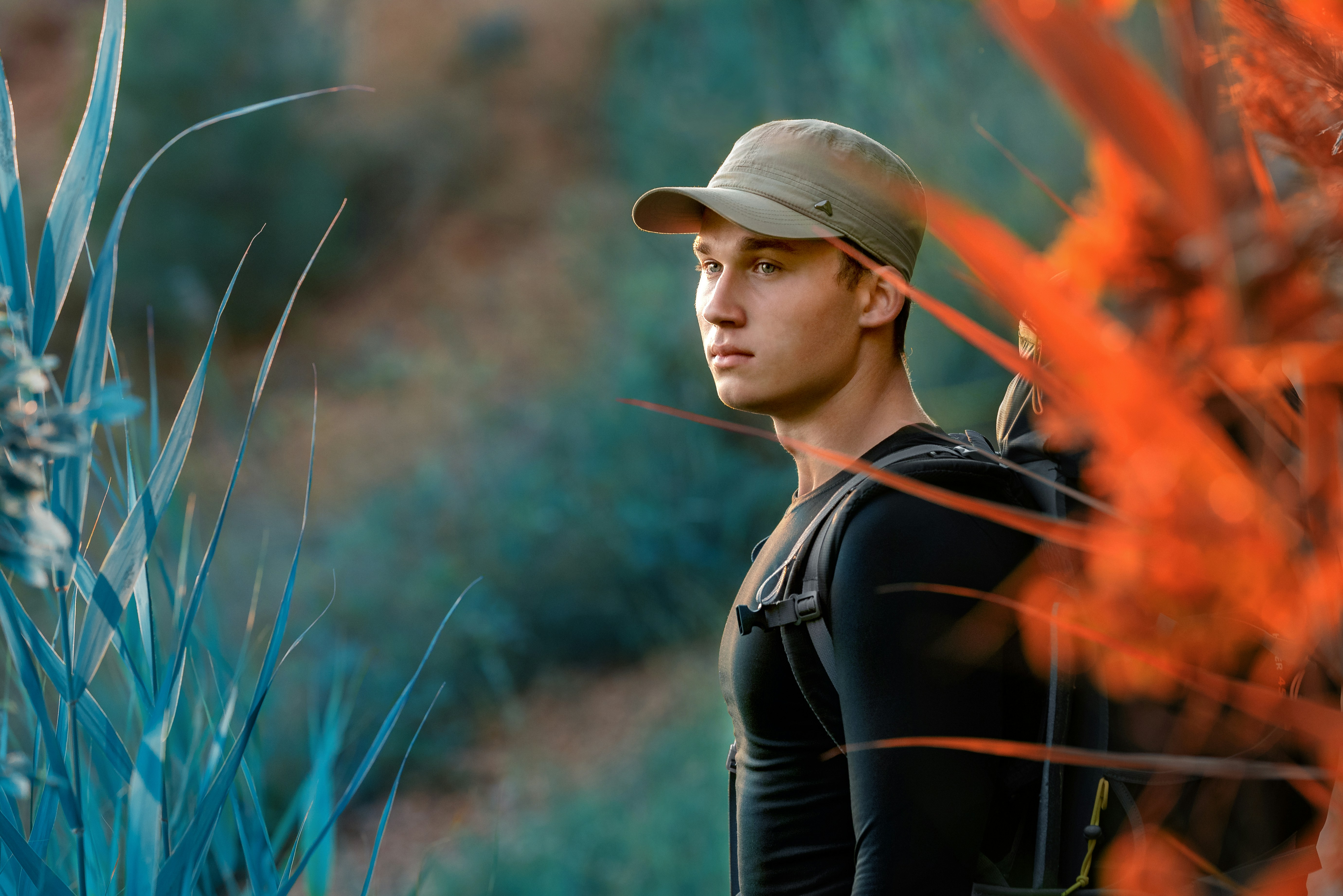 Young hiker stands amidst vibrant foliage, showcasing a blend of colors that highlight the natural surroundings. The scene captures a tranquil moment in the wilderness.