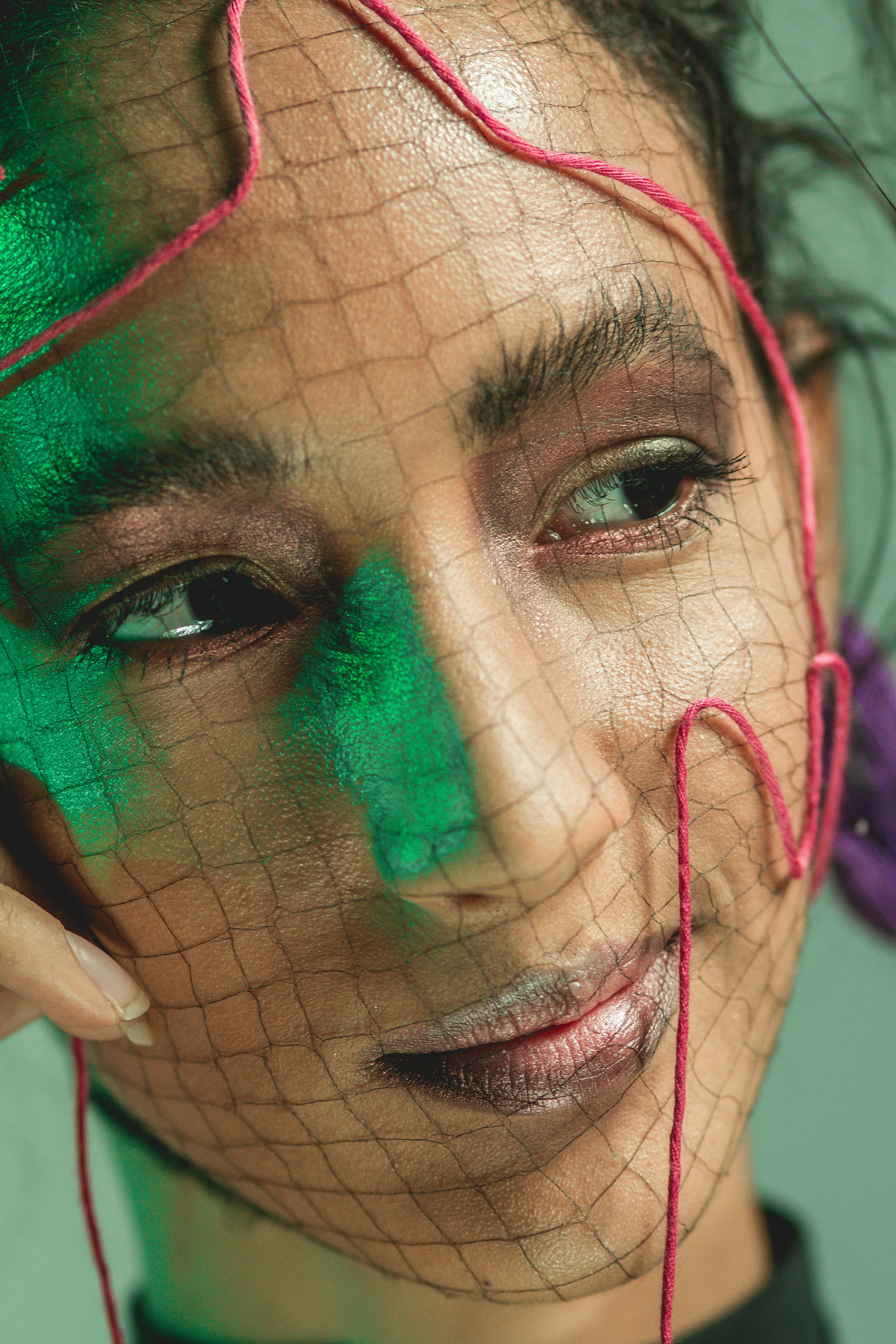 Veiled Gaze: Green Paint and Netting in a Close-Up Portrait