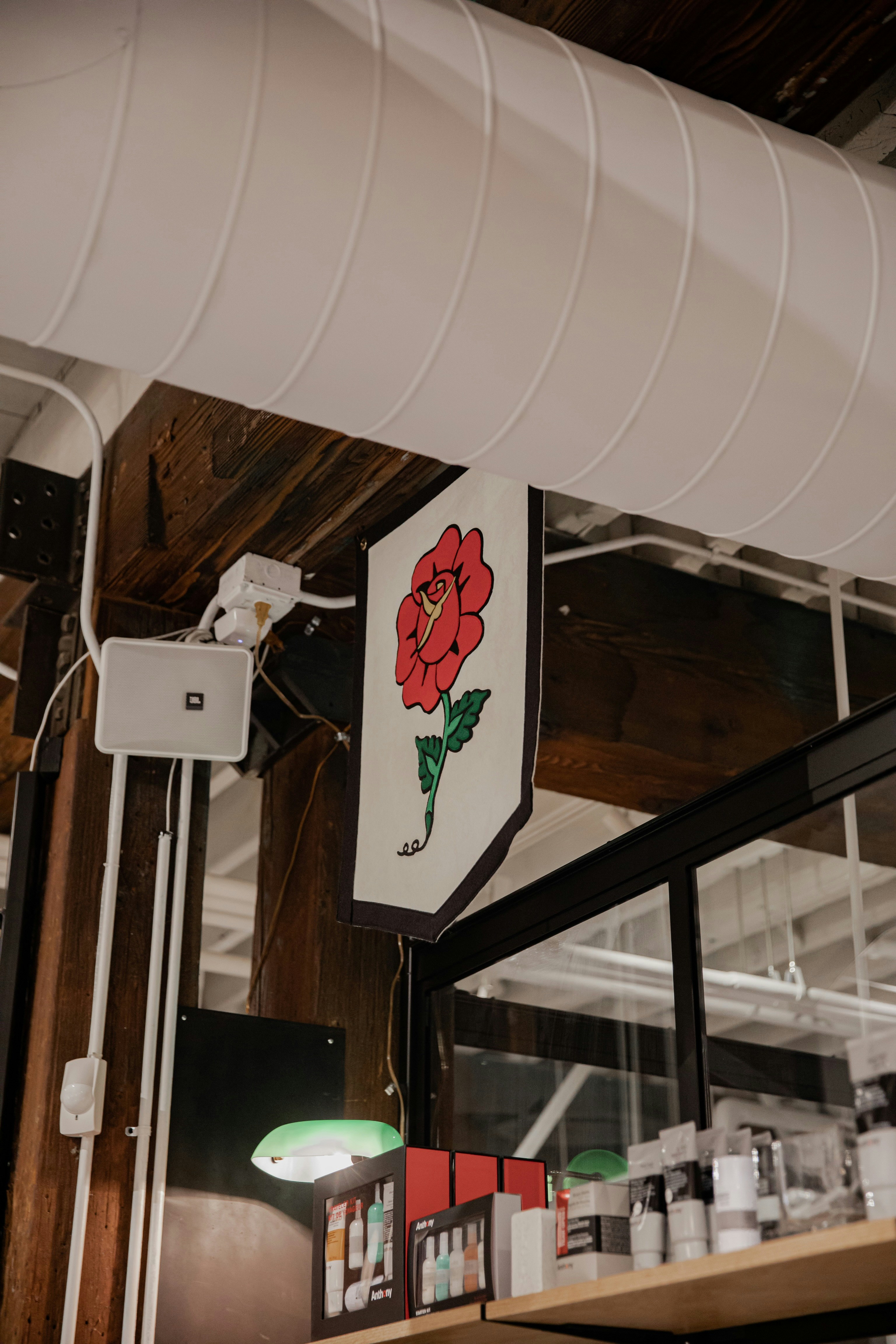 Hanging banner with a red rose illustration in an industrial-style interior.