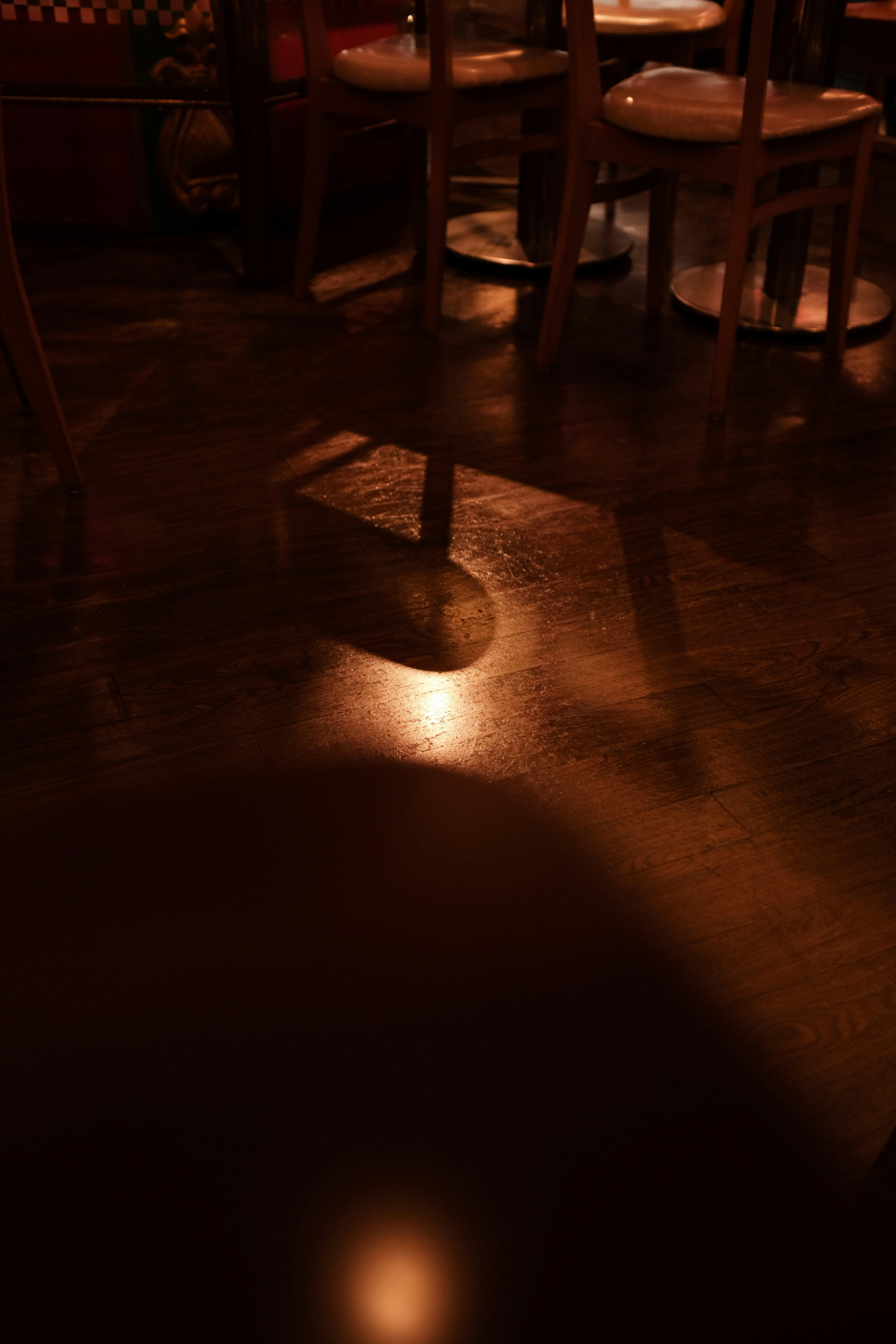 Soft reflections cast on polished wooden floor in an intimate setting, hinting at a tranquil atmosphere. The interplay of light and shadow creates a warm ambiance.