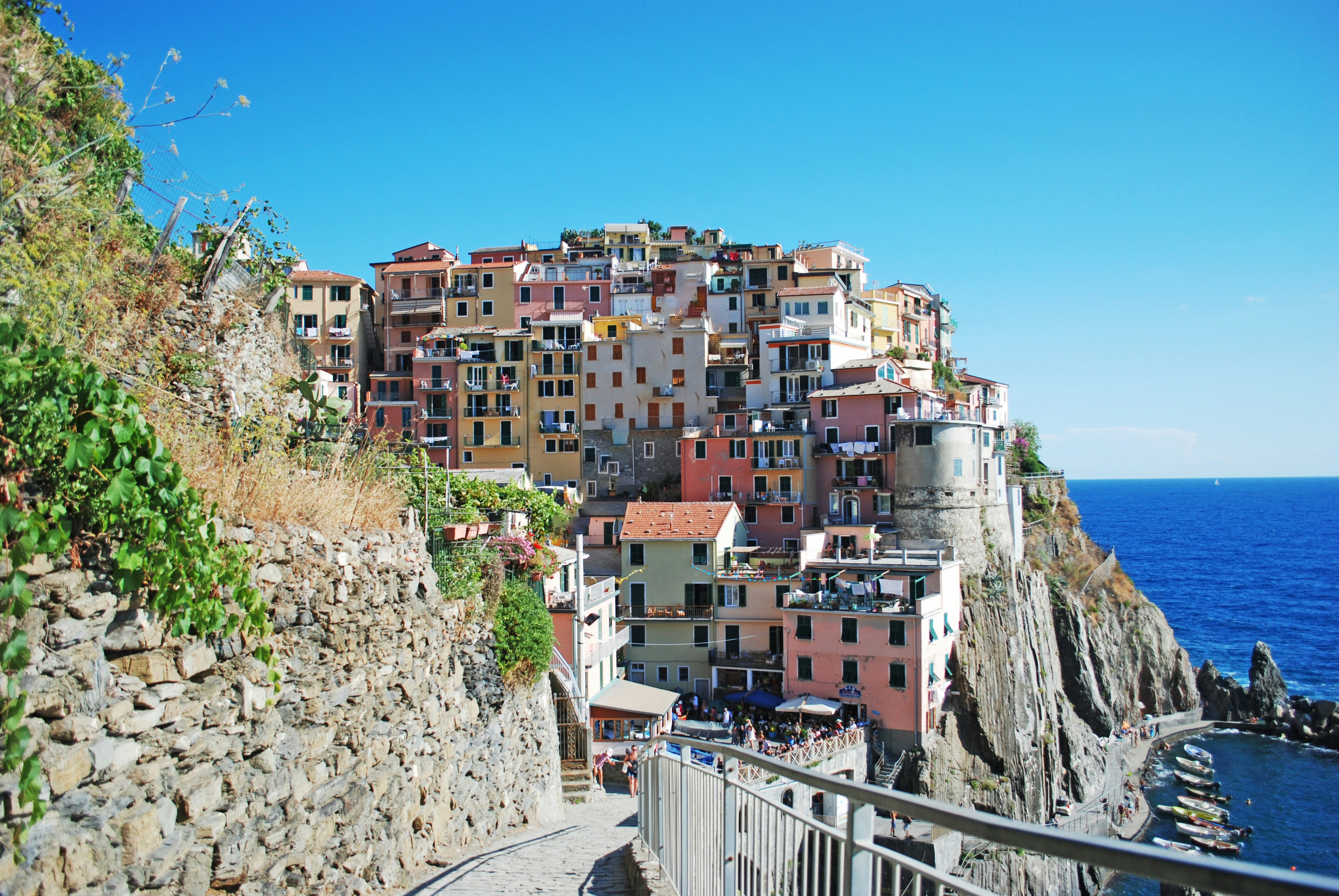 Colorful hillside village overlooking a rocky coastline with vibrant blue skies and ocean.