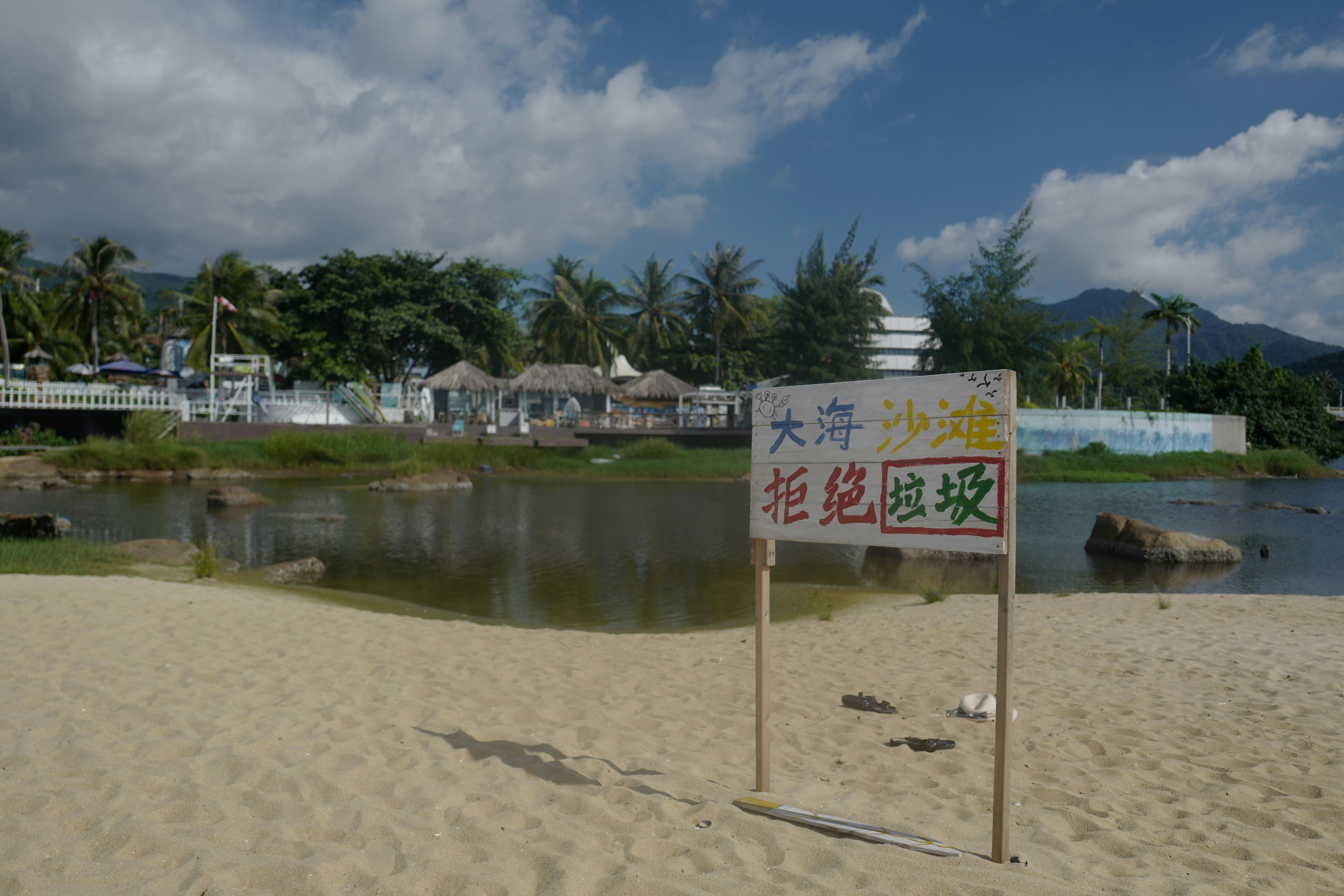 white and red signage on brown sand near body of water during daytime
