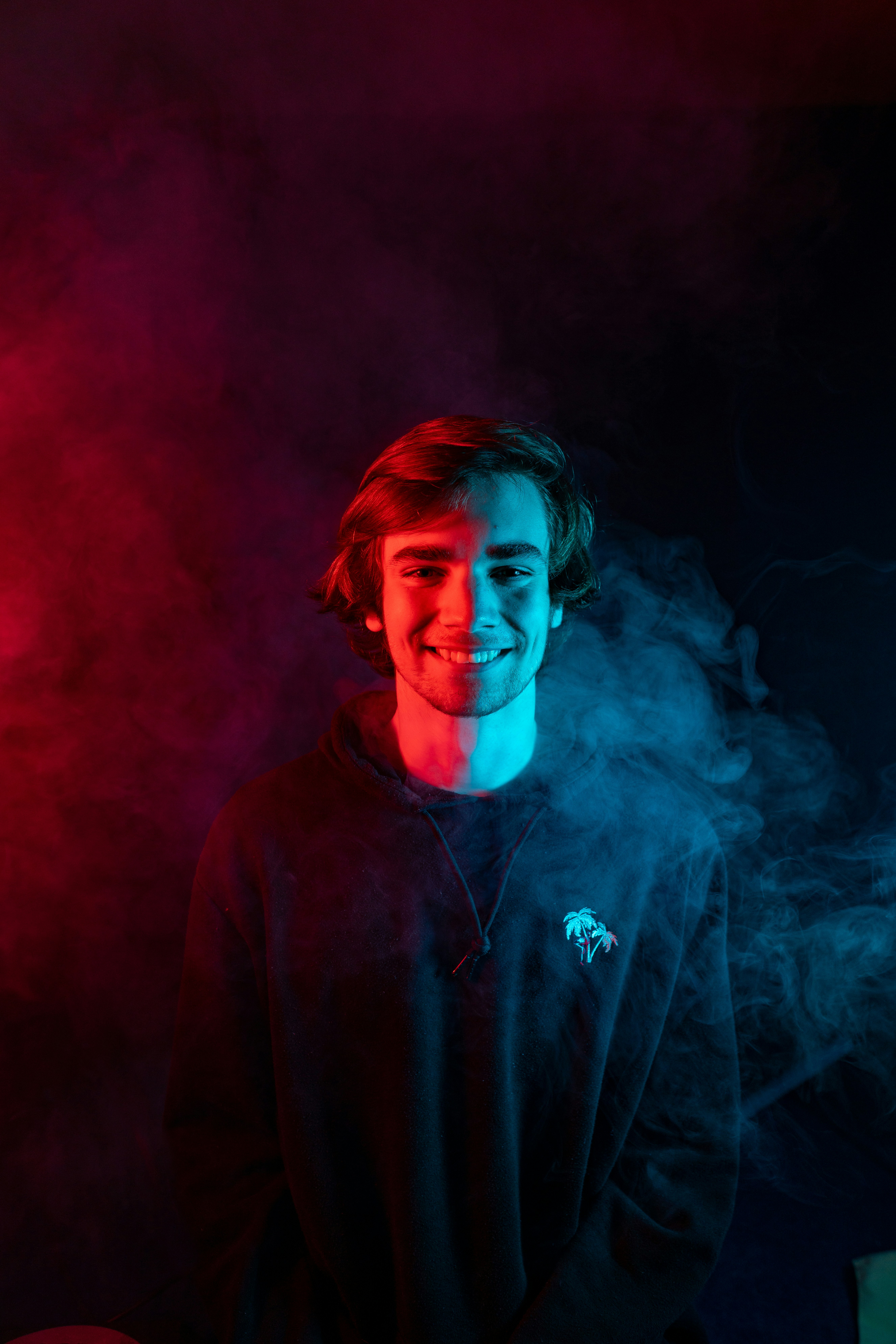 Neon Smoke Portrait: A Warm Smile Beneath Red and Cyan Lights